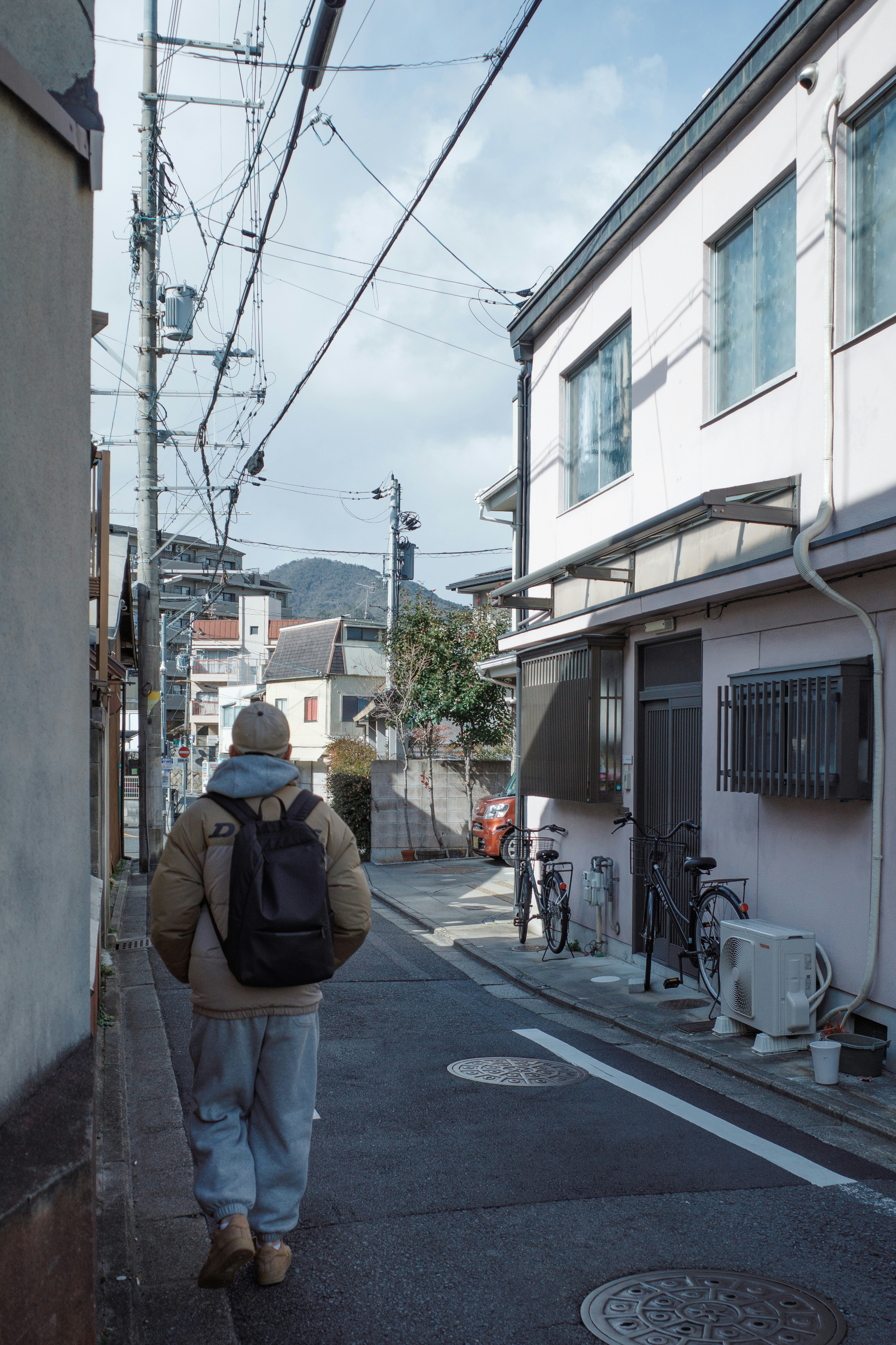 A person walks down a narrow city street.