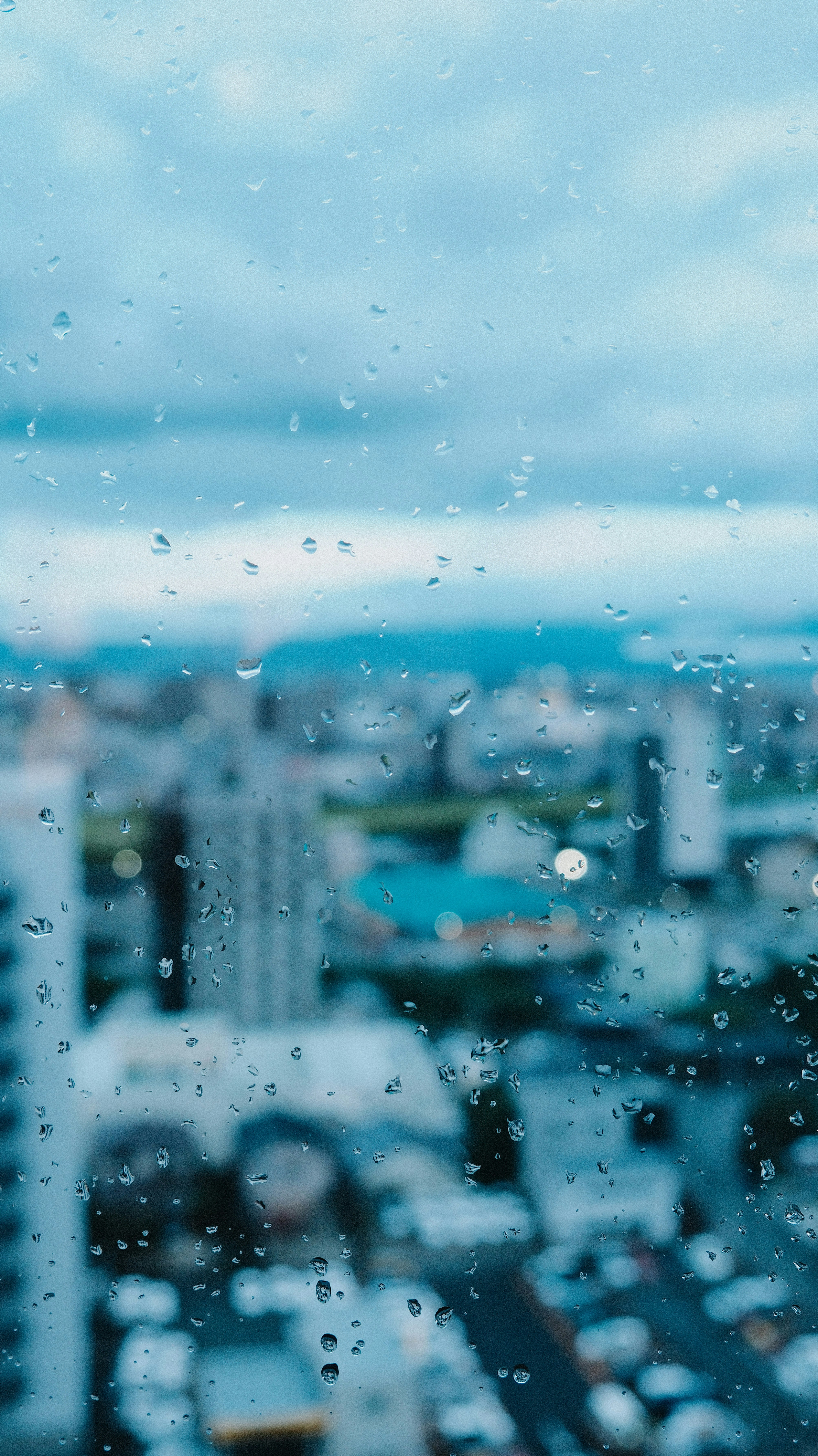 Raindrops on a window overlooking a city.