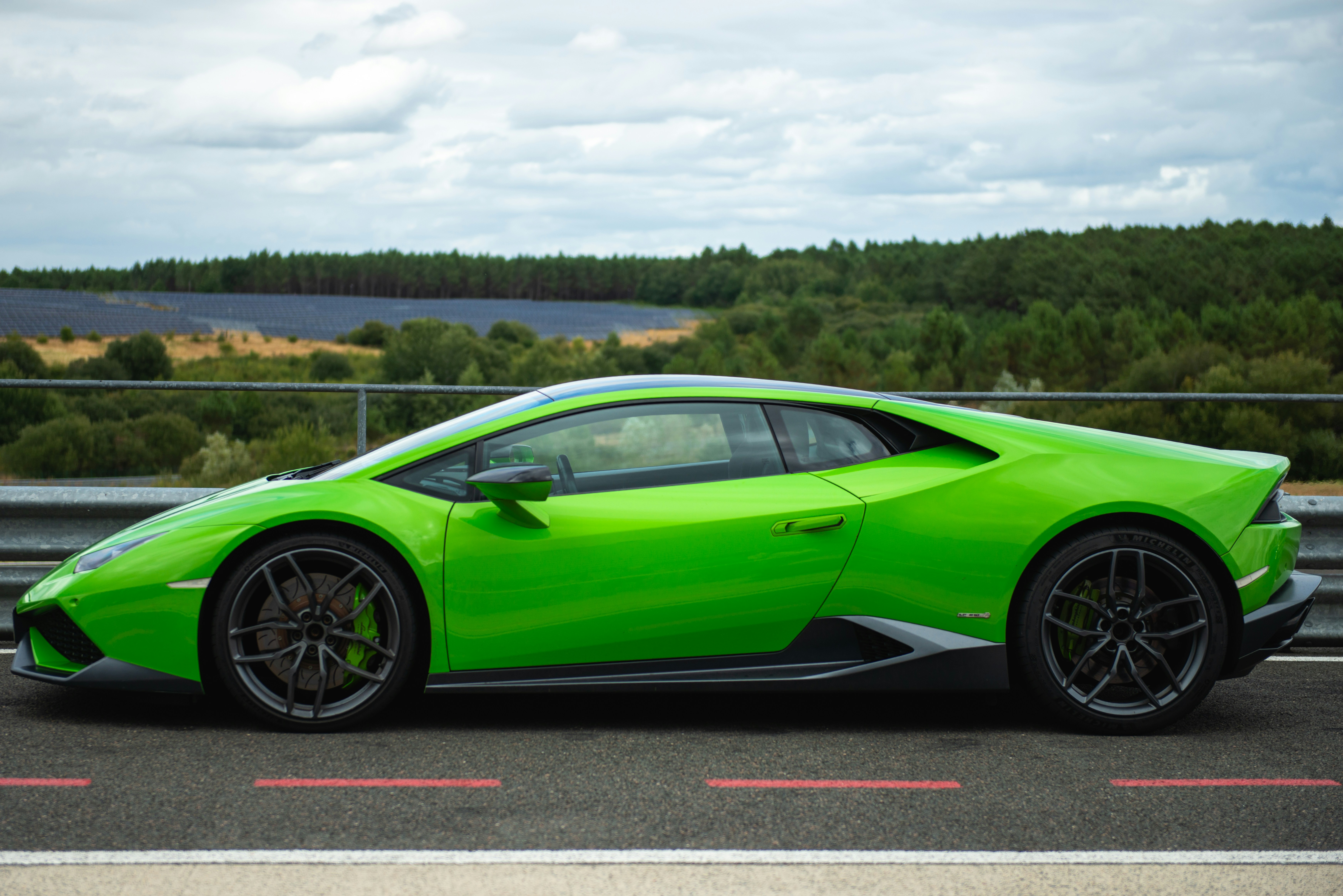 Vibrant green sports car showcased against a backdrop of lush greenery and cloudy skies.
