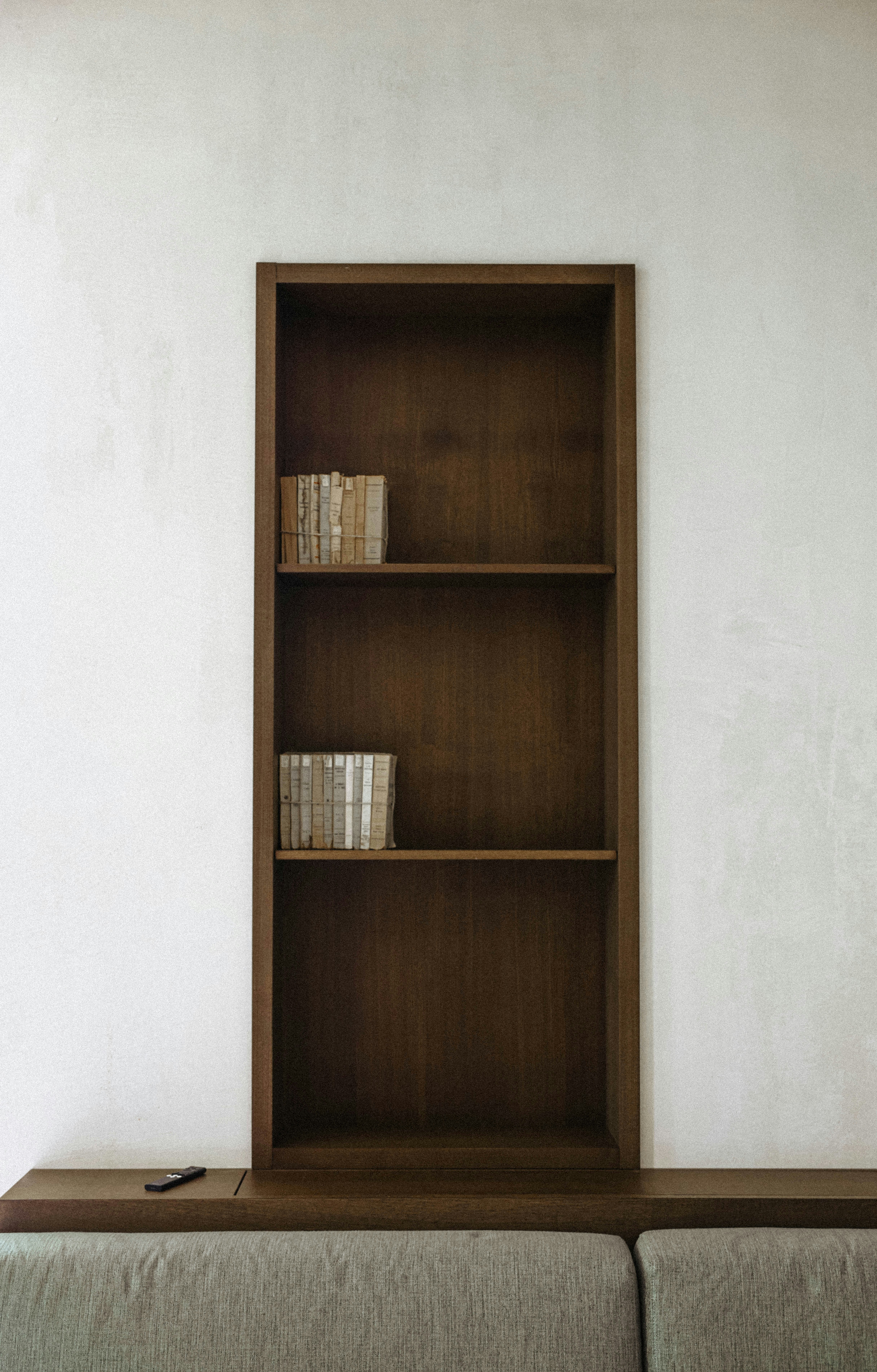 home decor, interior minimalism, wooden shelf | Wooden bookshelf with two stacks of books inside.