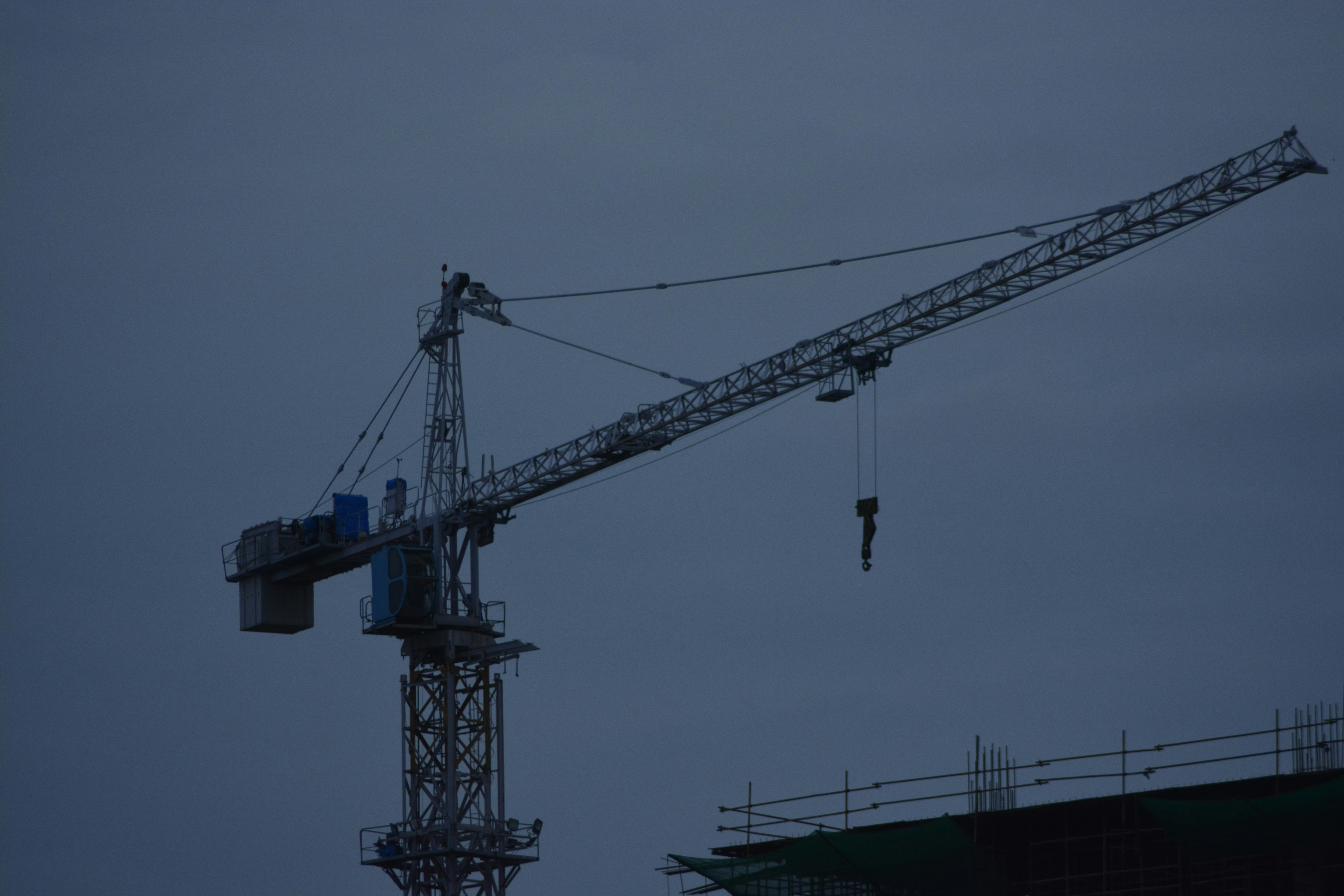 A construction crane stands silhouetted against the sky.