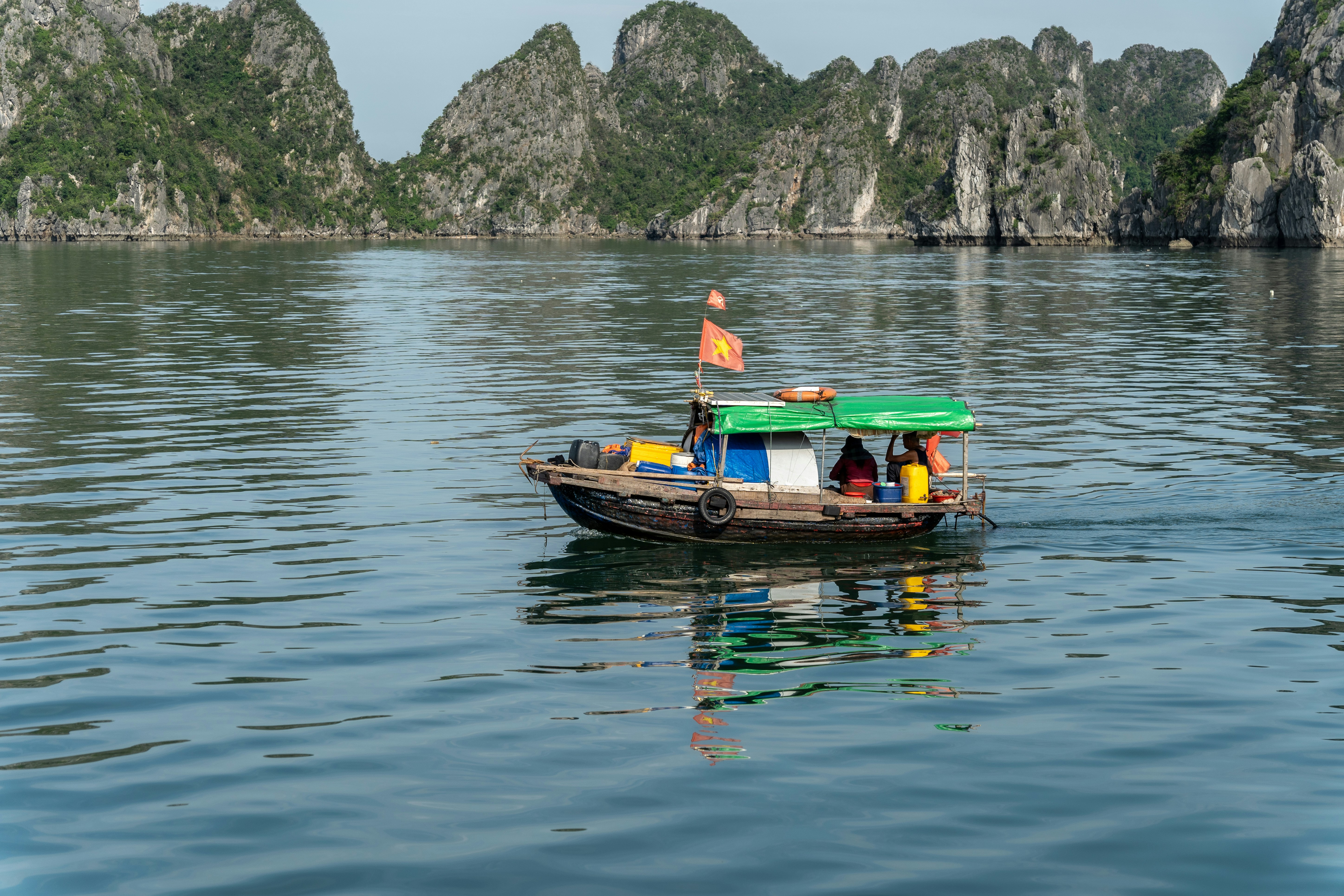 A small fishing boat on Ha Long Bay | A boat sails among majestic limestone islands.