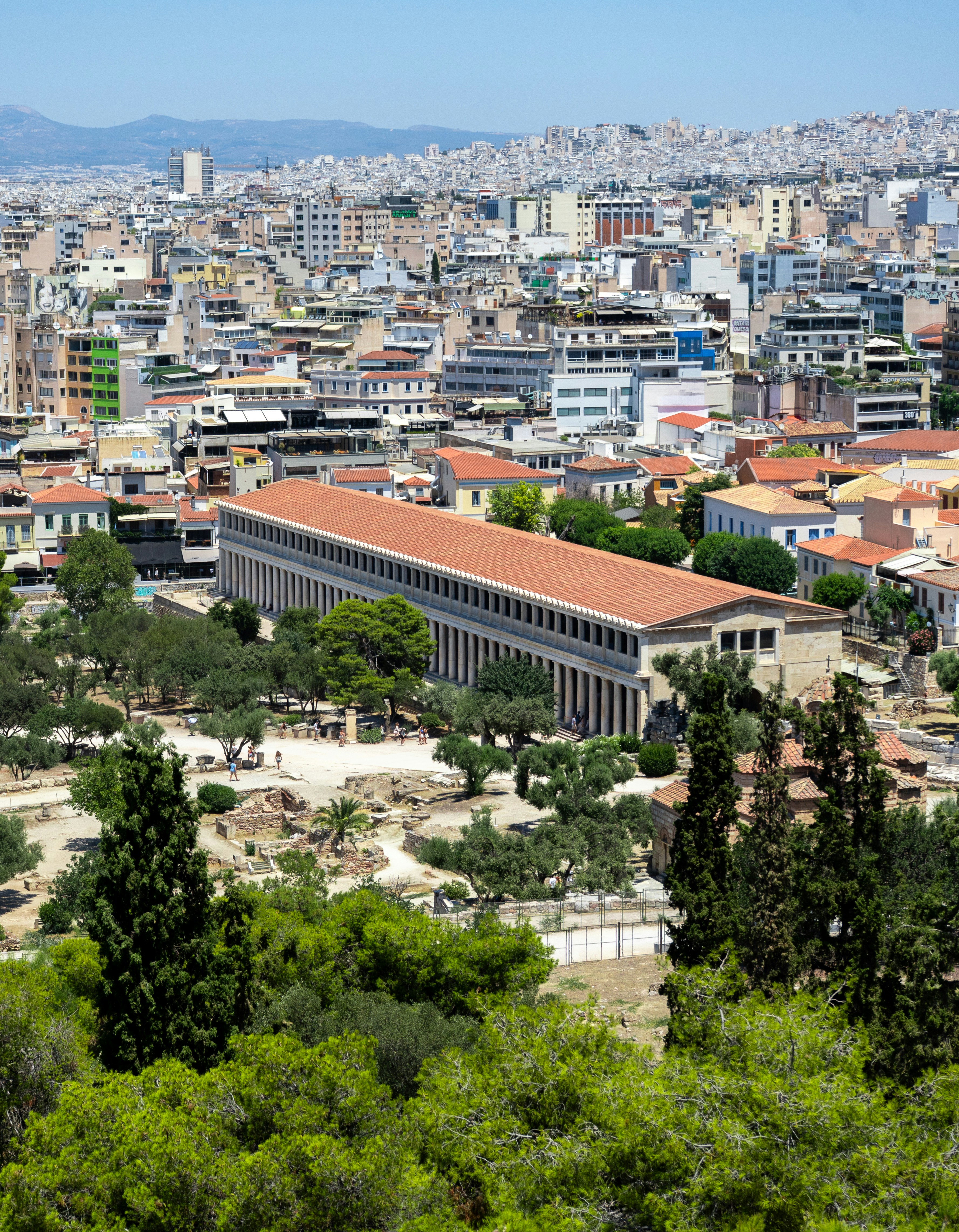 A long building sits among athens' cityscape.
