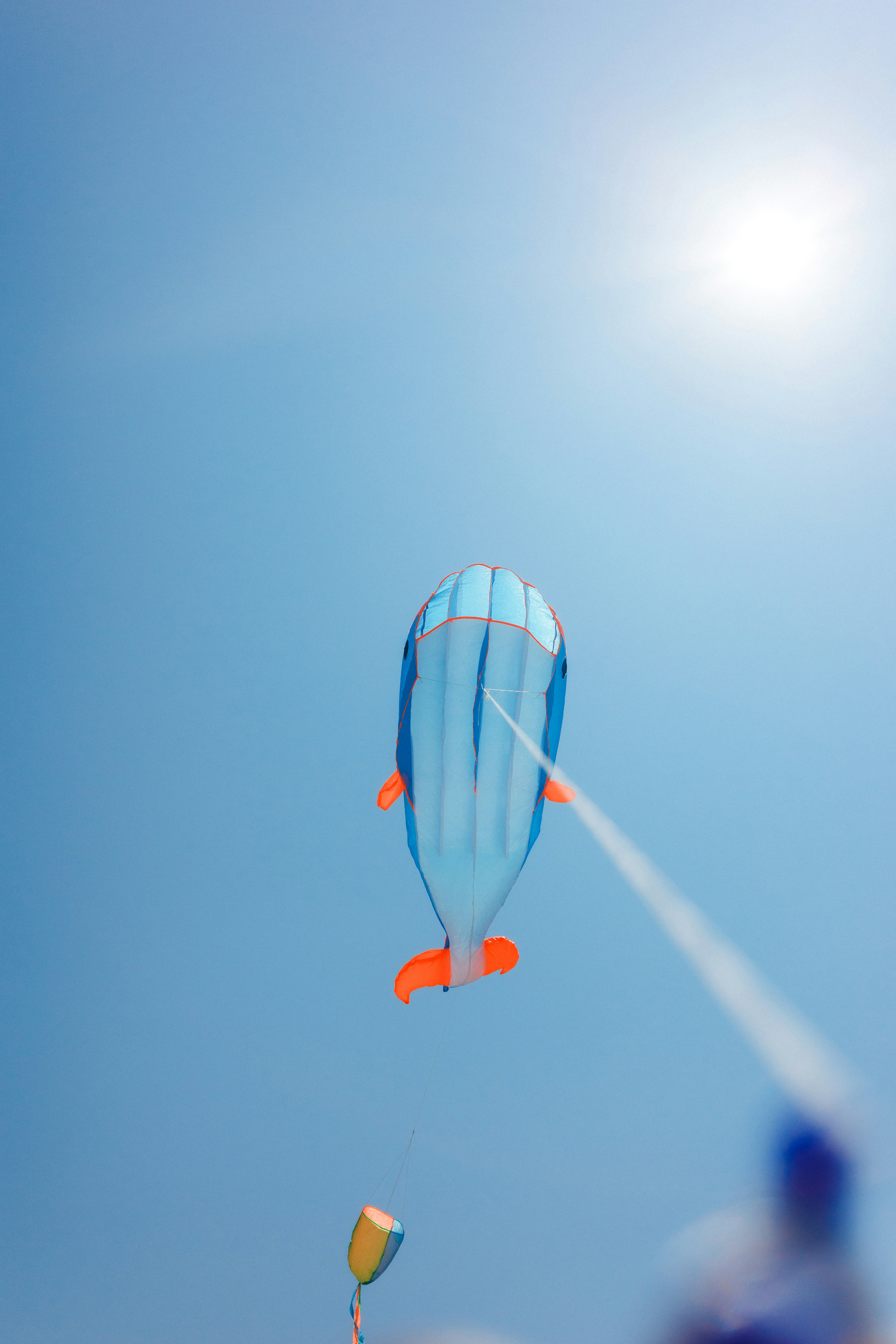 A blue kite flies high in the sky.