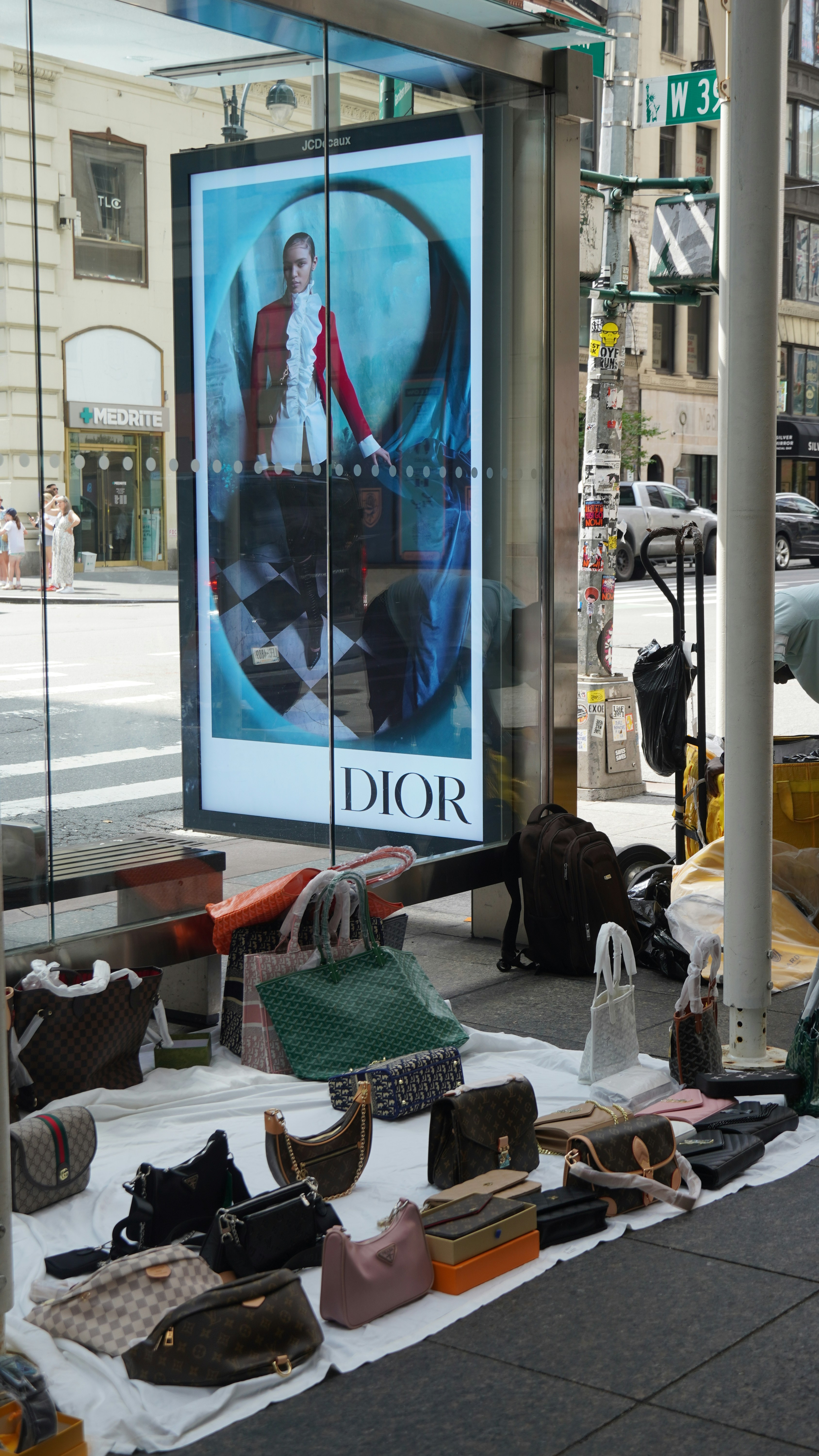Counterfeit bags on display in front of a dior ad.