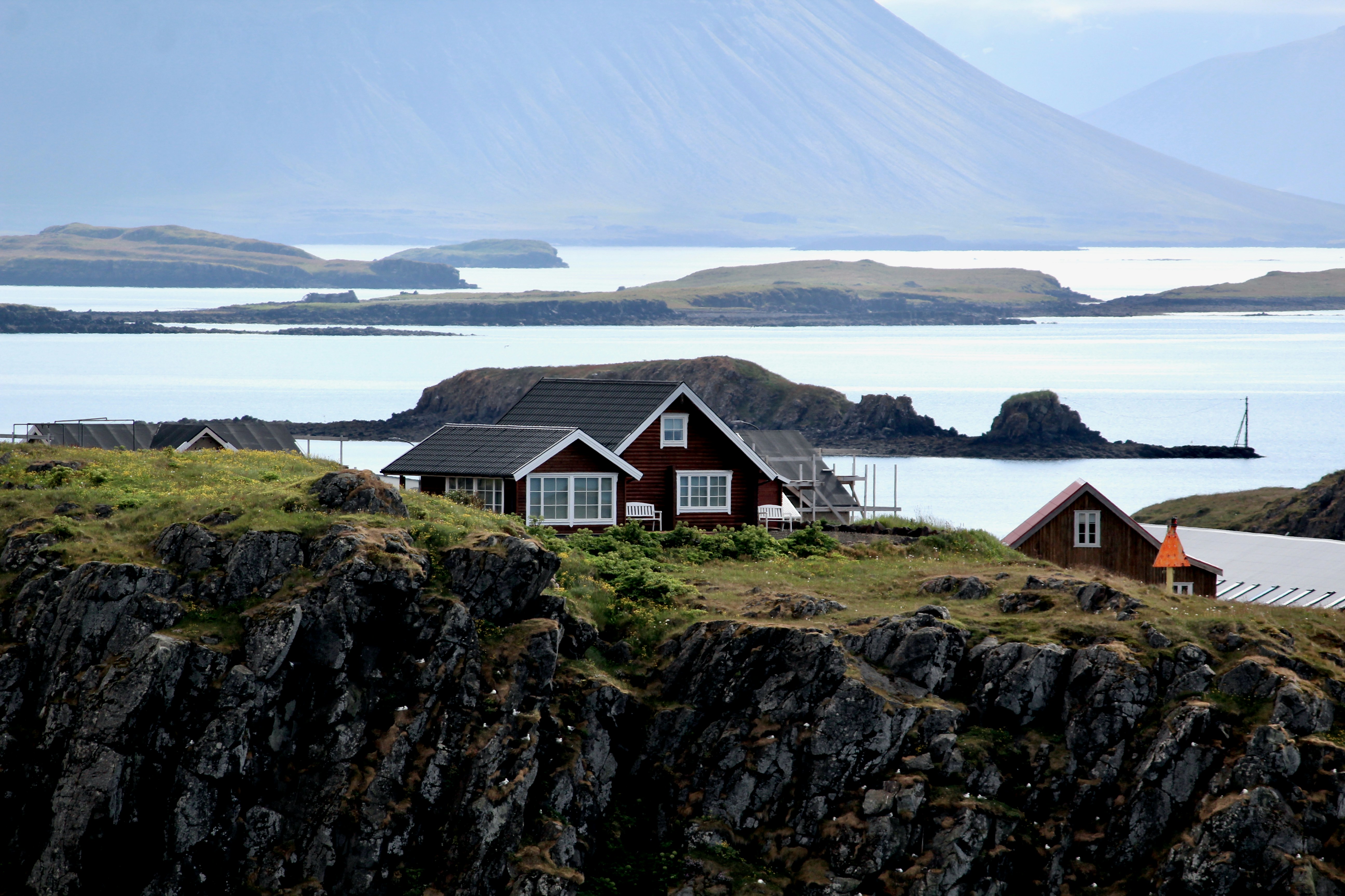House of a cliff at a fishing town in Iceland | Houses sit on a cliff overlooking the water.