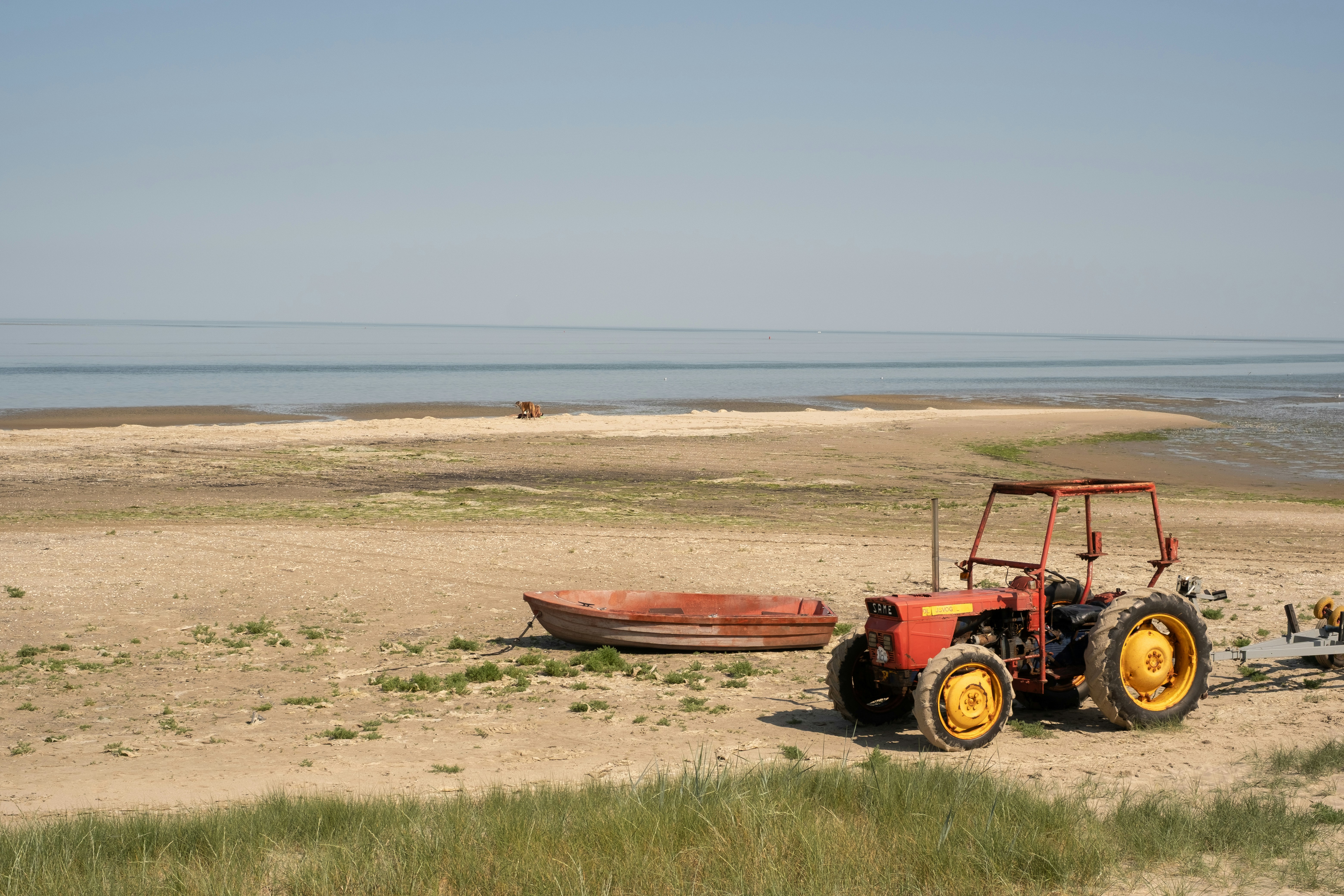 A tractor and boat on a sandy shore.