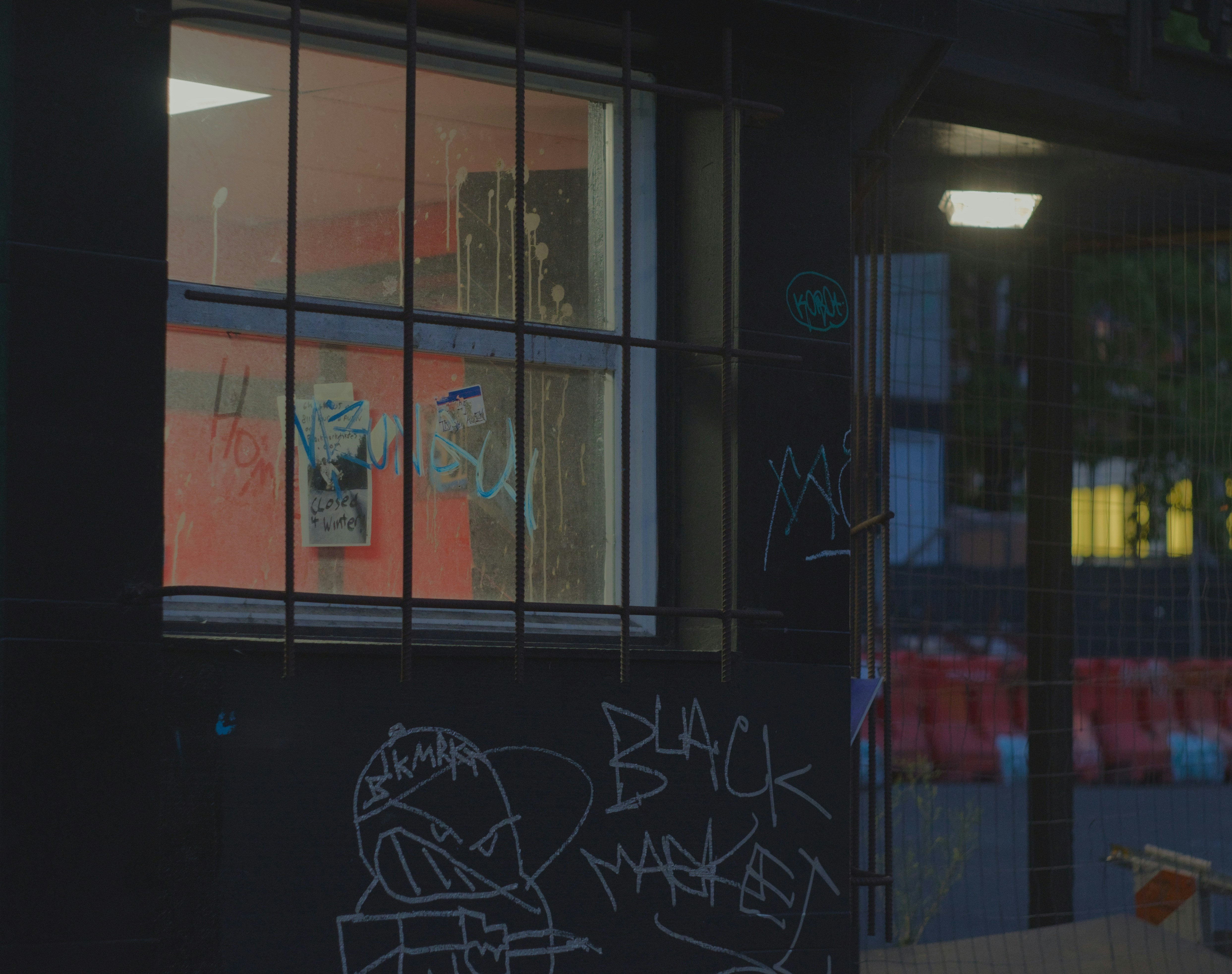 Graffiti covers a building window with bars.