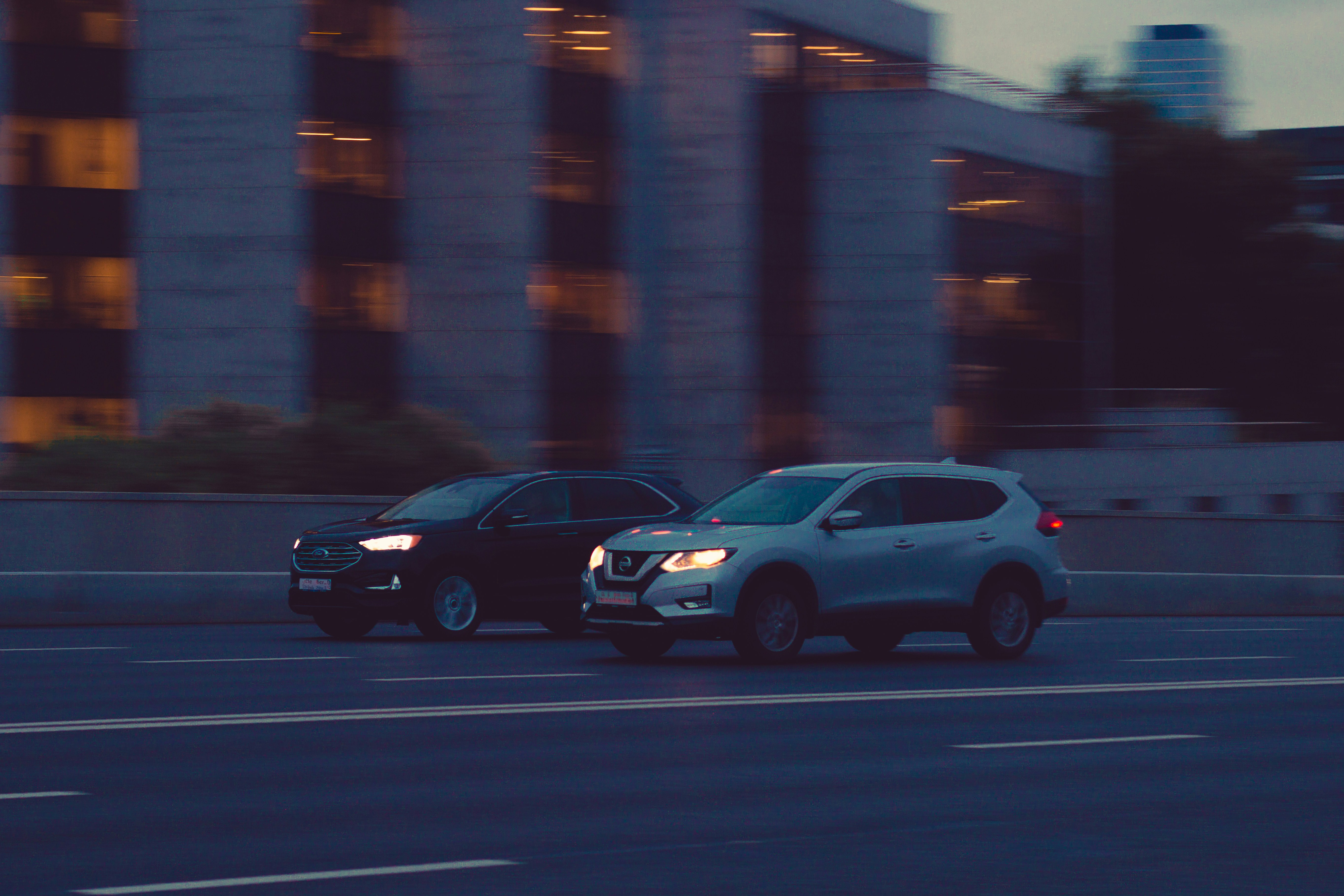 Two suvs drive on a road at dusk. photo – Free Highway Image on Unsplash