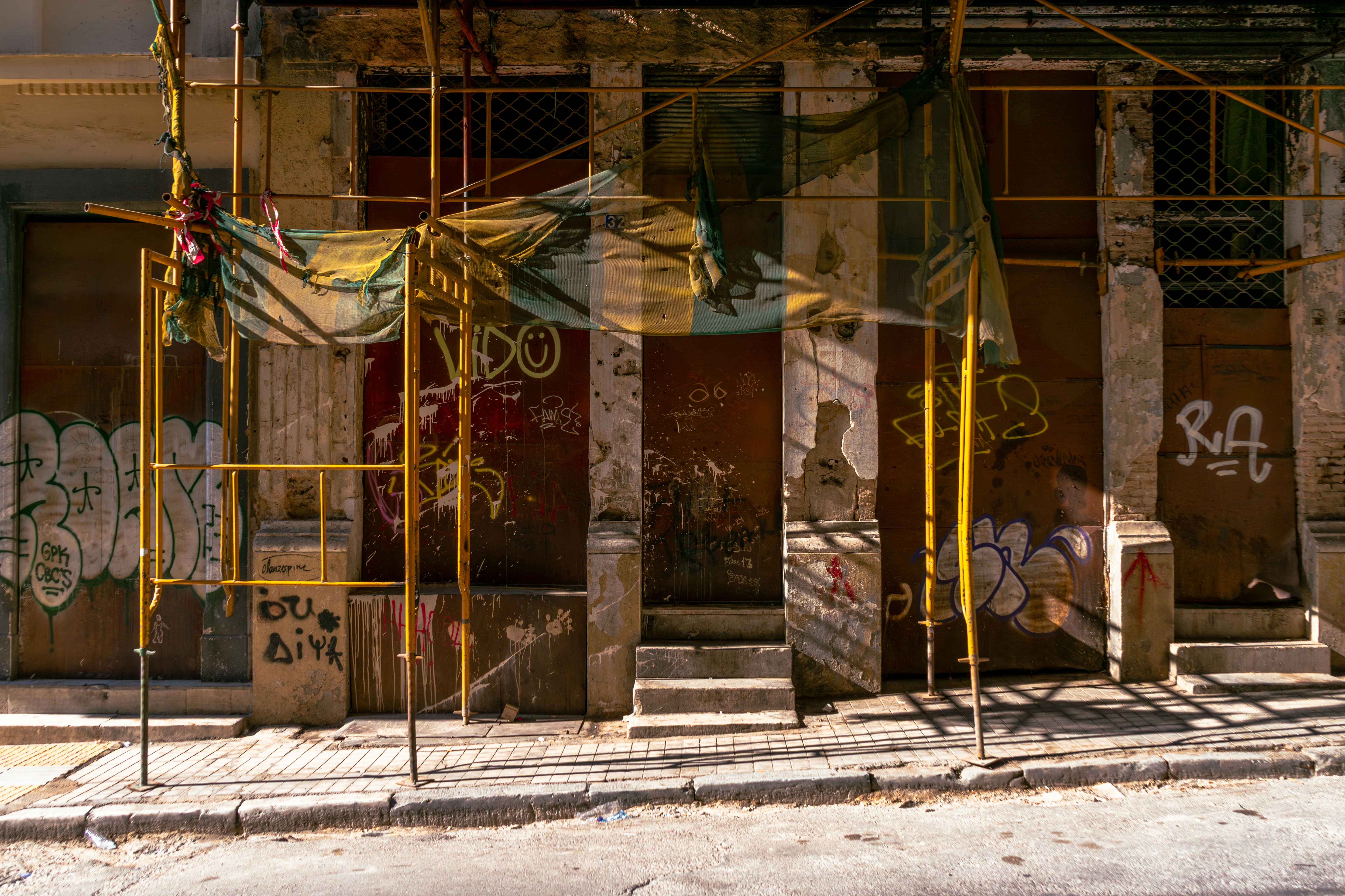Graffitied Facade under Sunlit Scaffolding