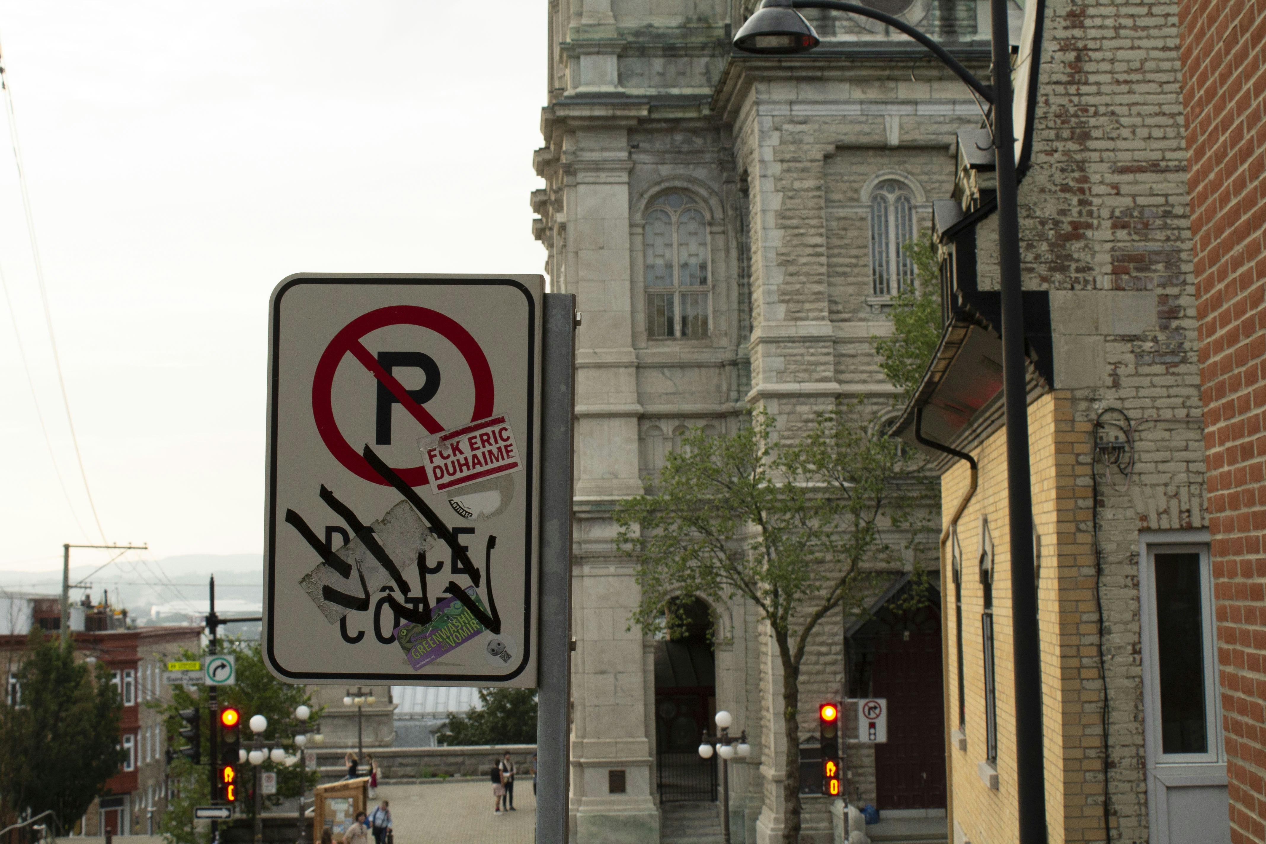 No parking sign stands beside a building.