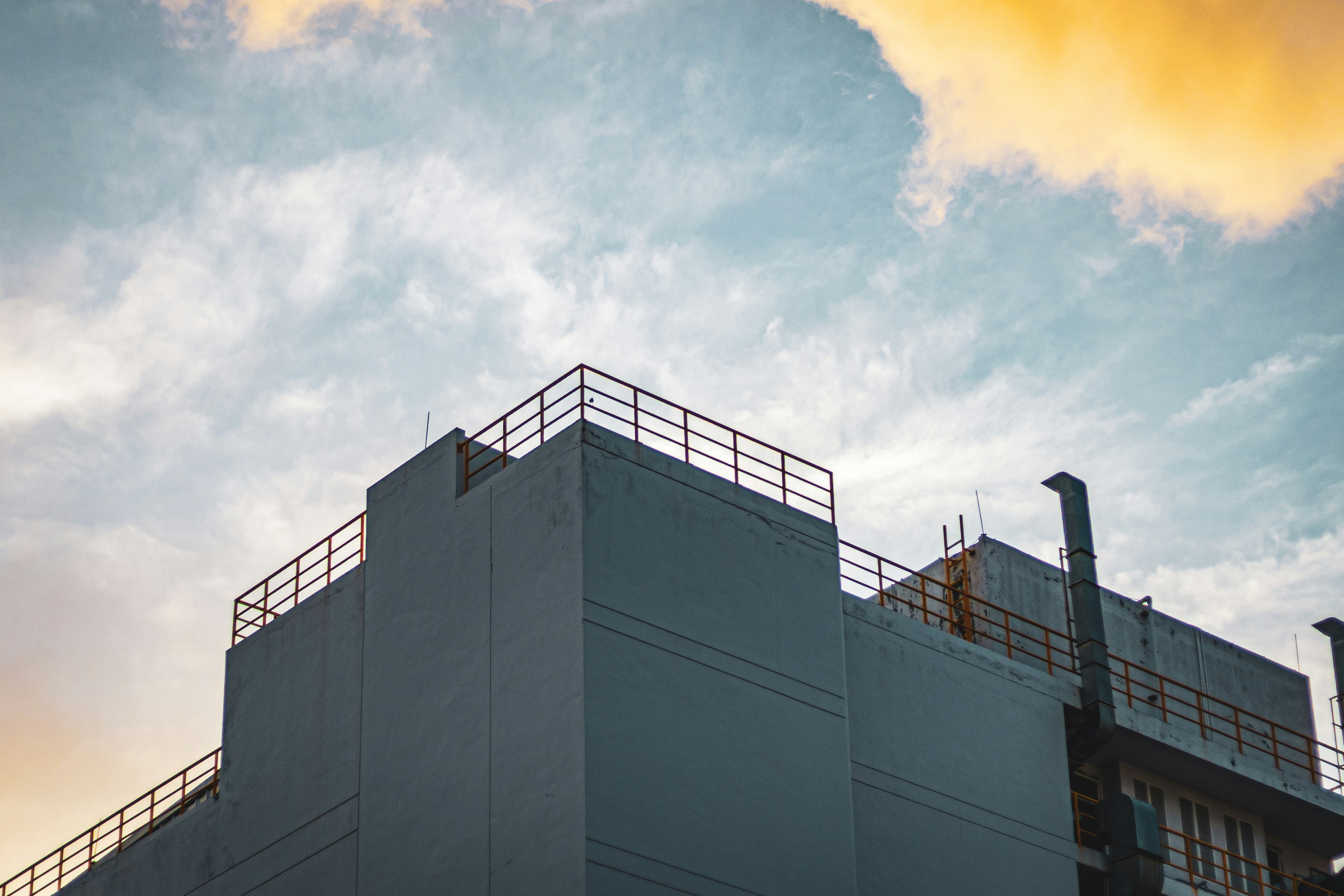 Abstract architectural silhouette against a vibrant sky, showcasing angular lines and contrasting colors. The scene captures the interplay of urban structures and atmospheric elements.