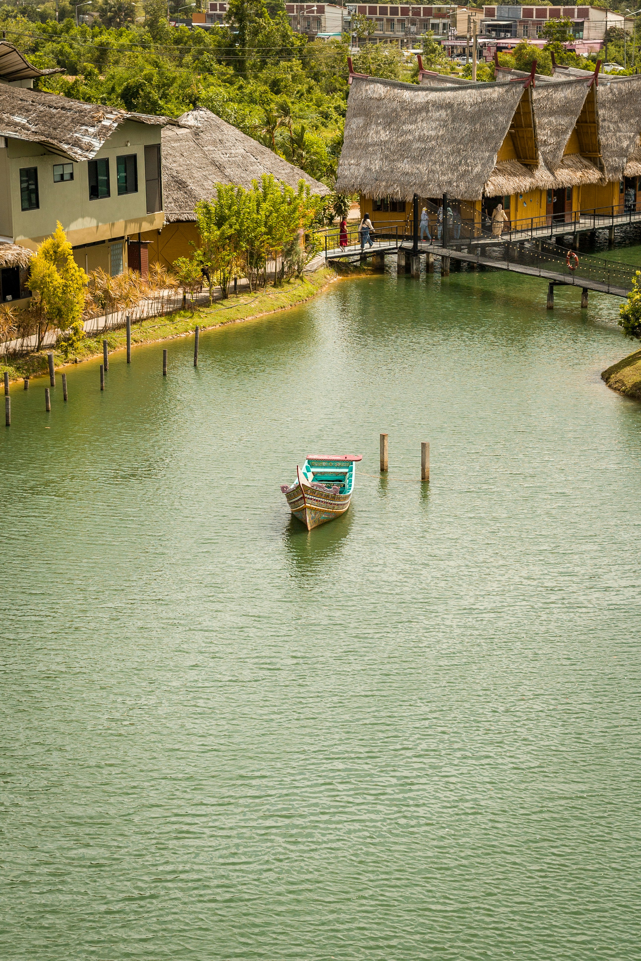 A boat floats near thatched roof buildings.