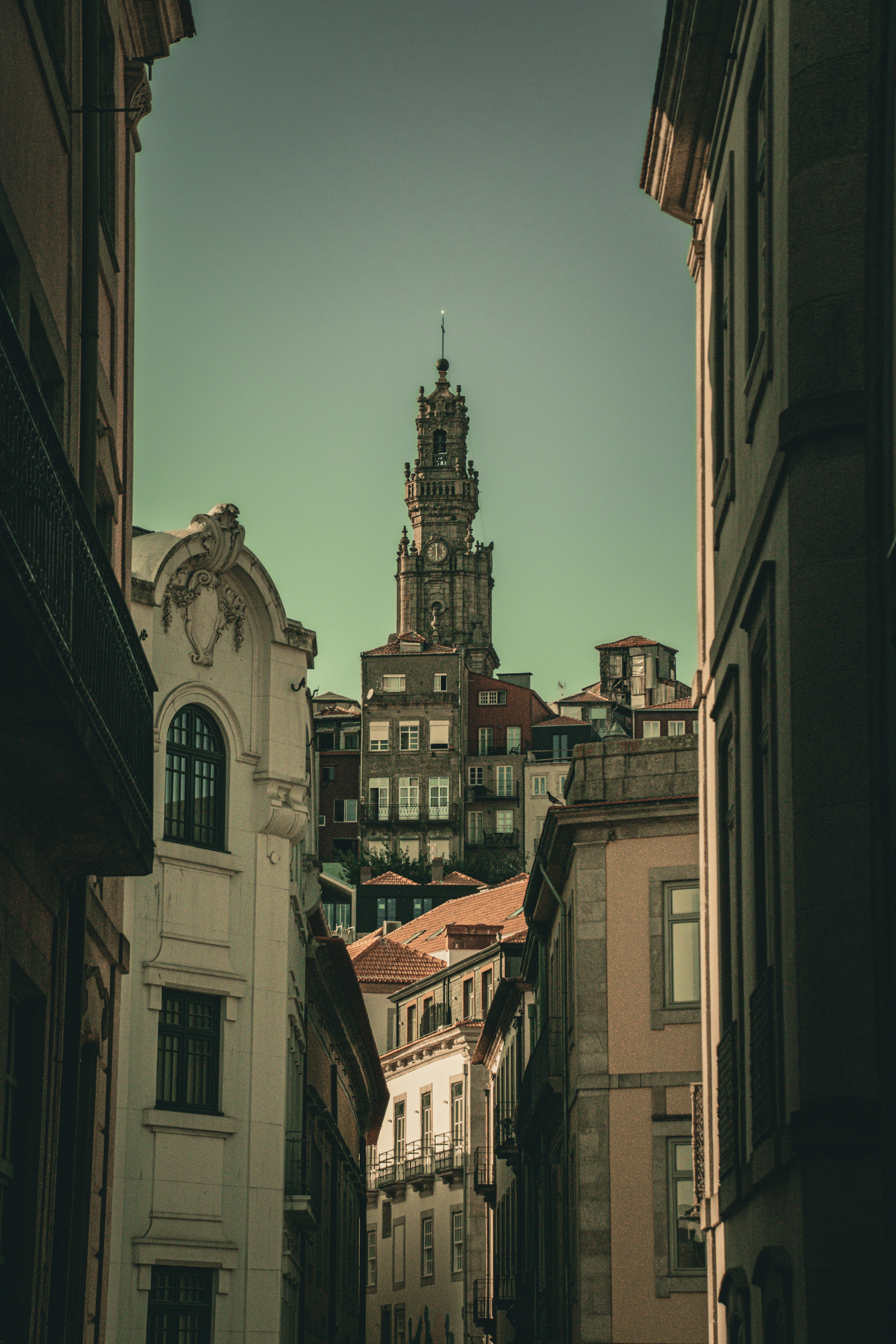 Torre dos Clérigos | A tower peeks above buildings in a narrow street.