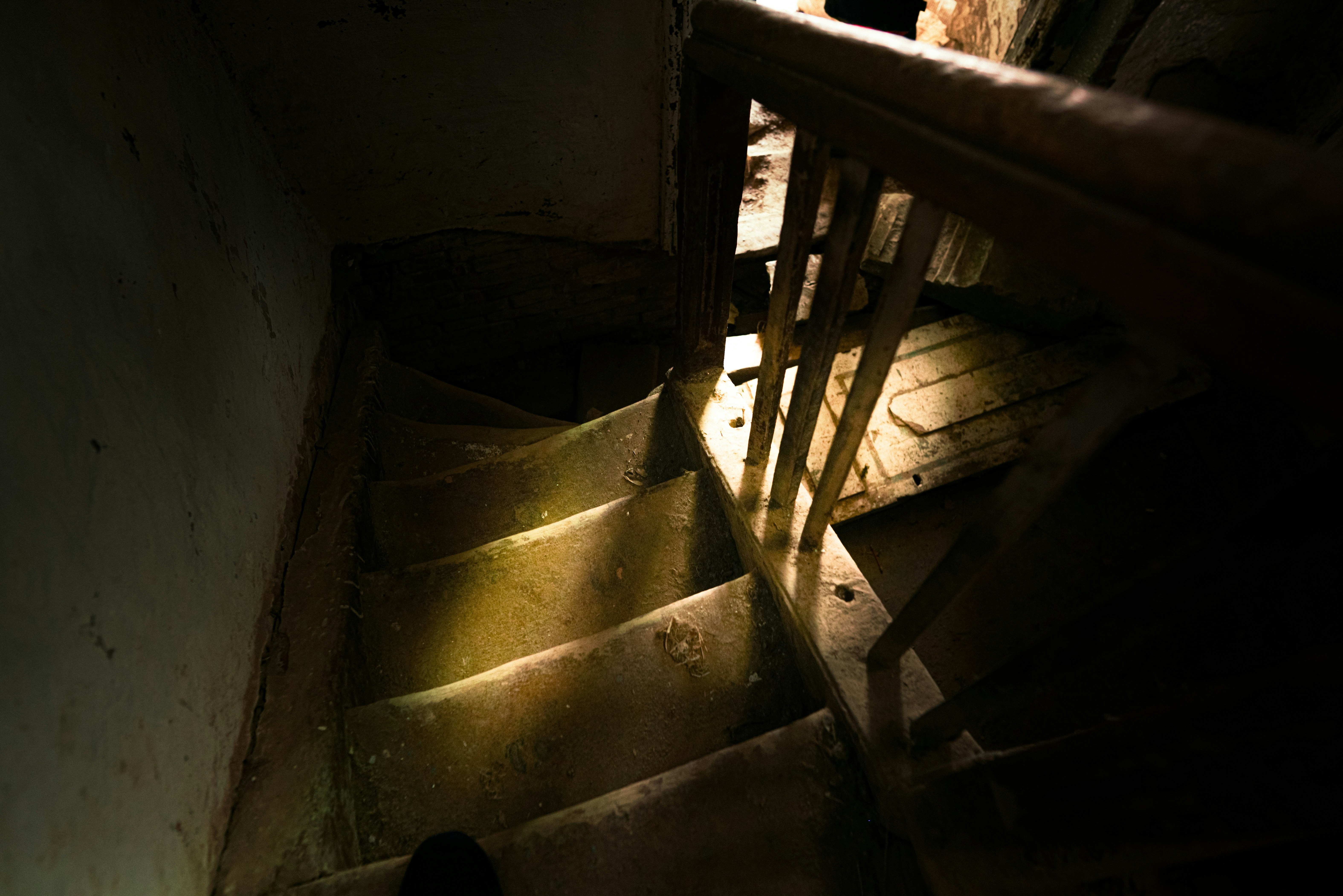 Dimly lit, aged stairs ascend into shadows.
