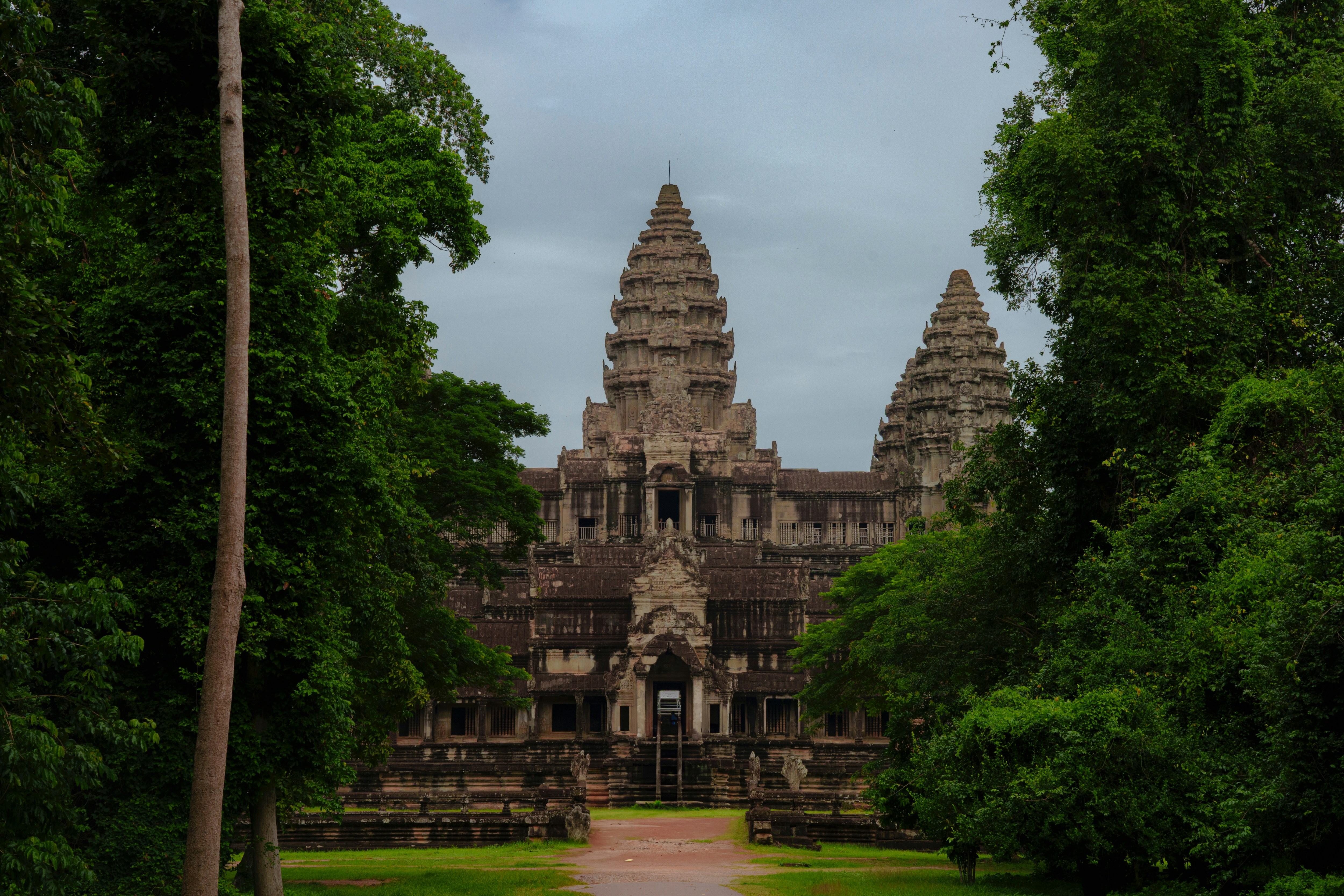#angkorwat #cambodia #siemreap #angkor #angkorwattemple #travel #khmer #siemreaptrip #travelphotography #phnompenh #angkortemples #streetclassics #cambodiatravel #asia #cambodiatrip #angkorwatcambodia #southeastasia #siemreapcambodia #temple #travelgram #beautifulcambodia #adventure #cambodian #explorecambodia #visitcambodia #angkordriver #SPICollective #wanderlust #angkorwatsunrise #streetphotographie | Angkor wat temple is framed by lush green trees.