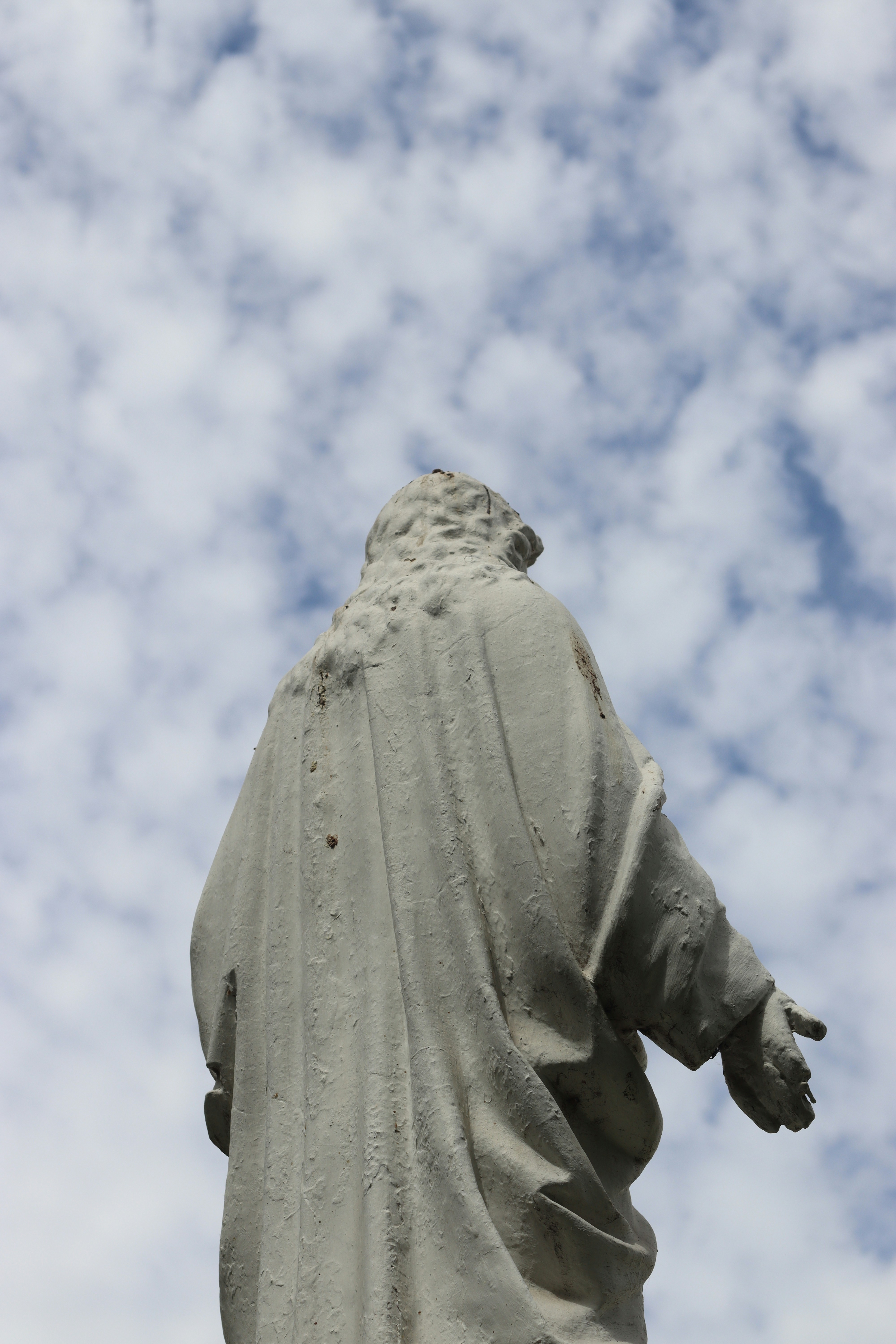 Statue of jesus against a cloudy blue sky.