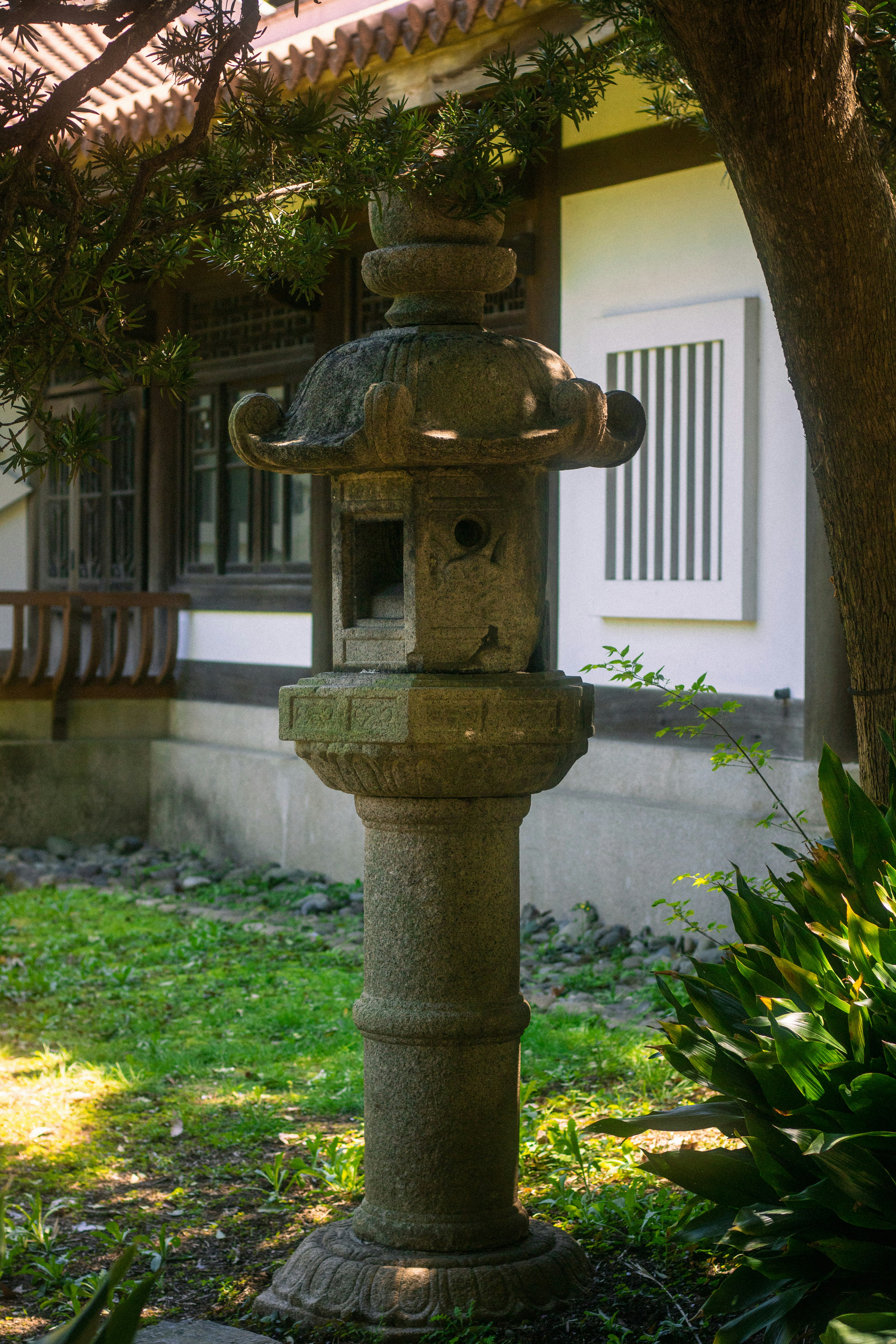 A japanese stone lantern stands in a peaceful garden.
