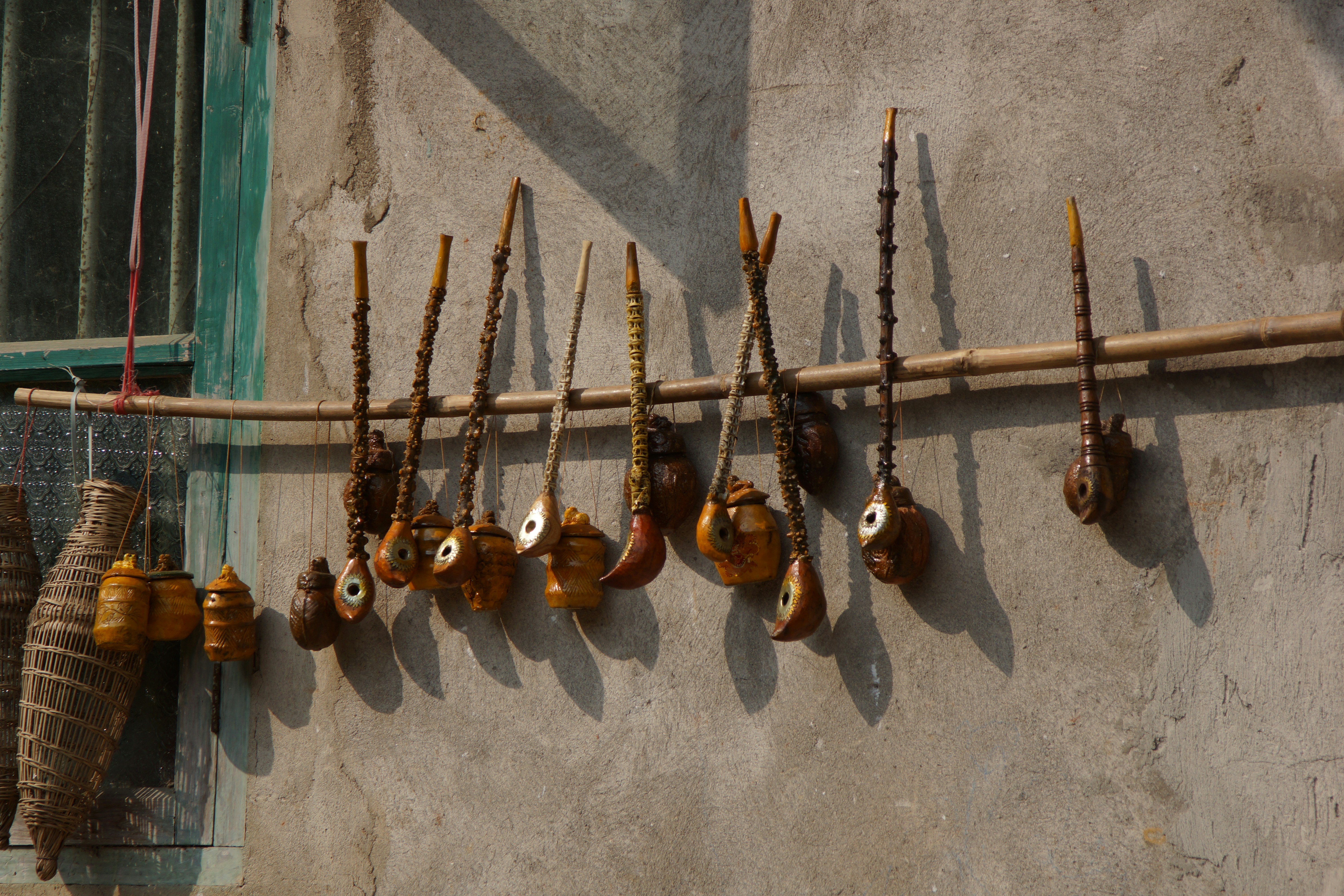 Musical instruments | Gourds and pipes hanging on a textured wall.