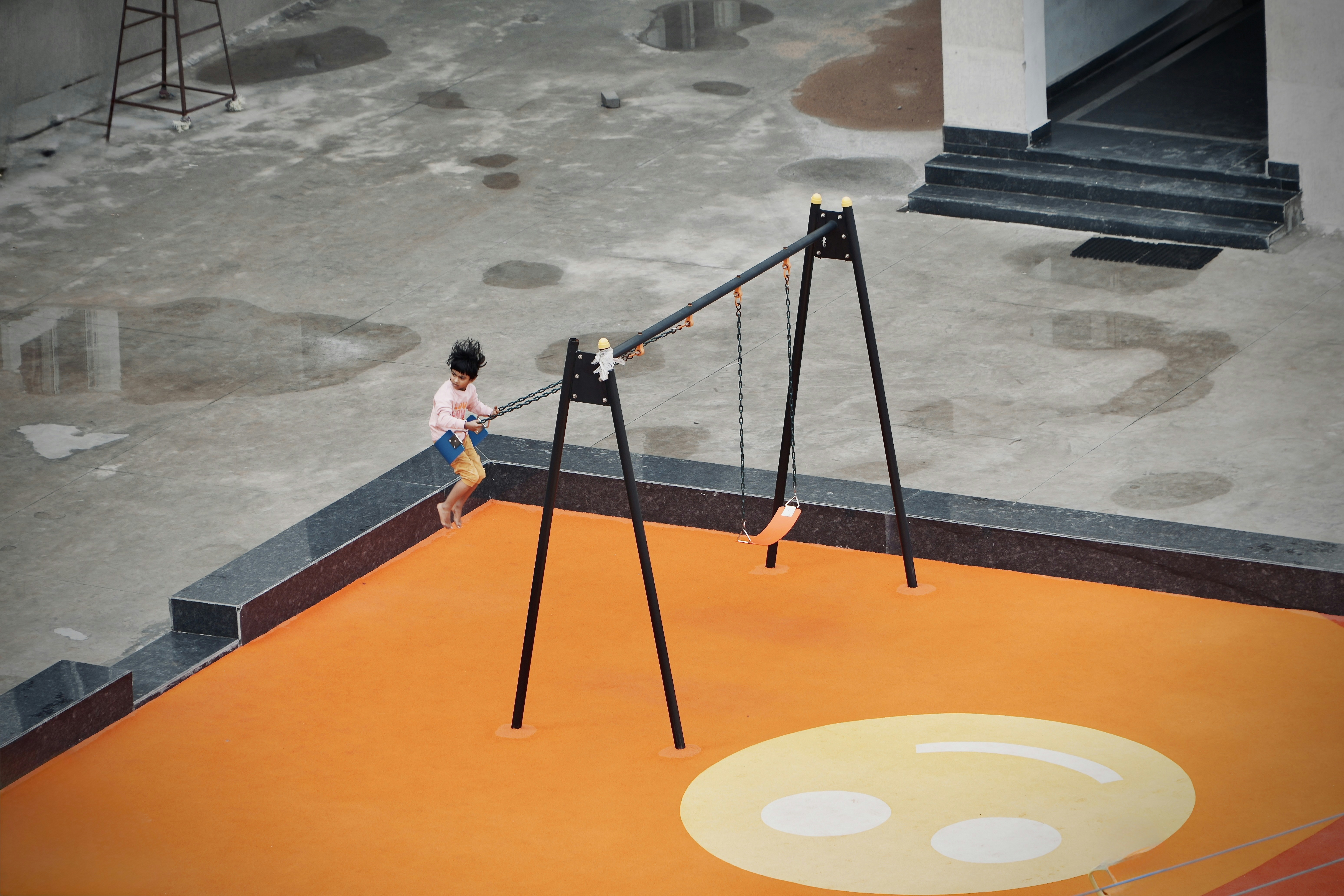 A girl playing | A child plays near a swing set.