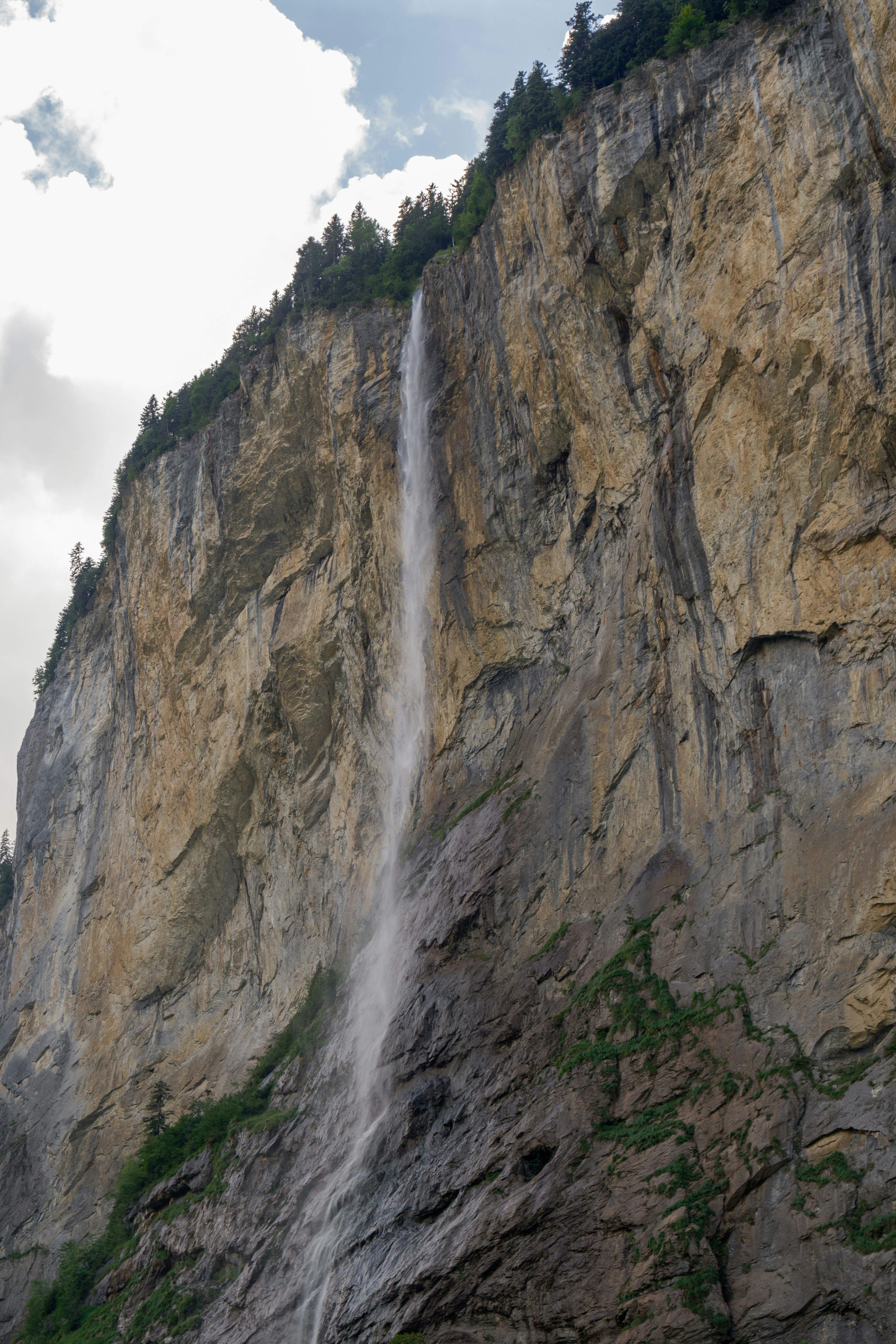 A majestic waterfall cascading down a rugged cliffside, surrounded by lush greenery and rocky terrain.