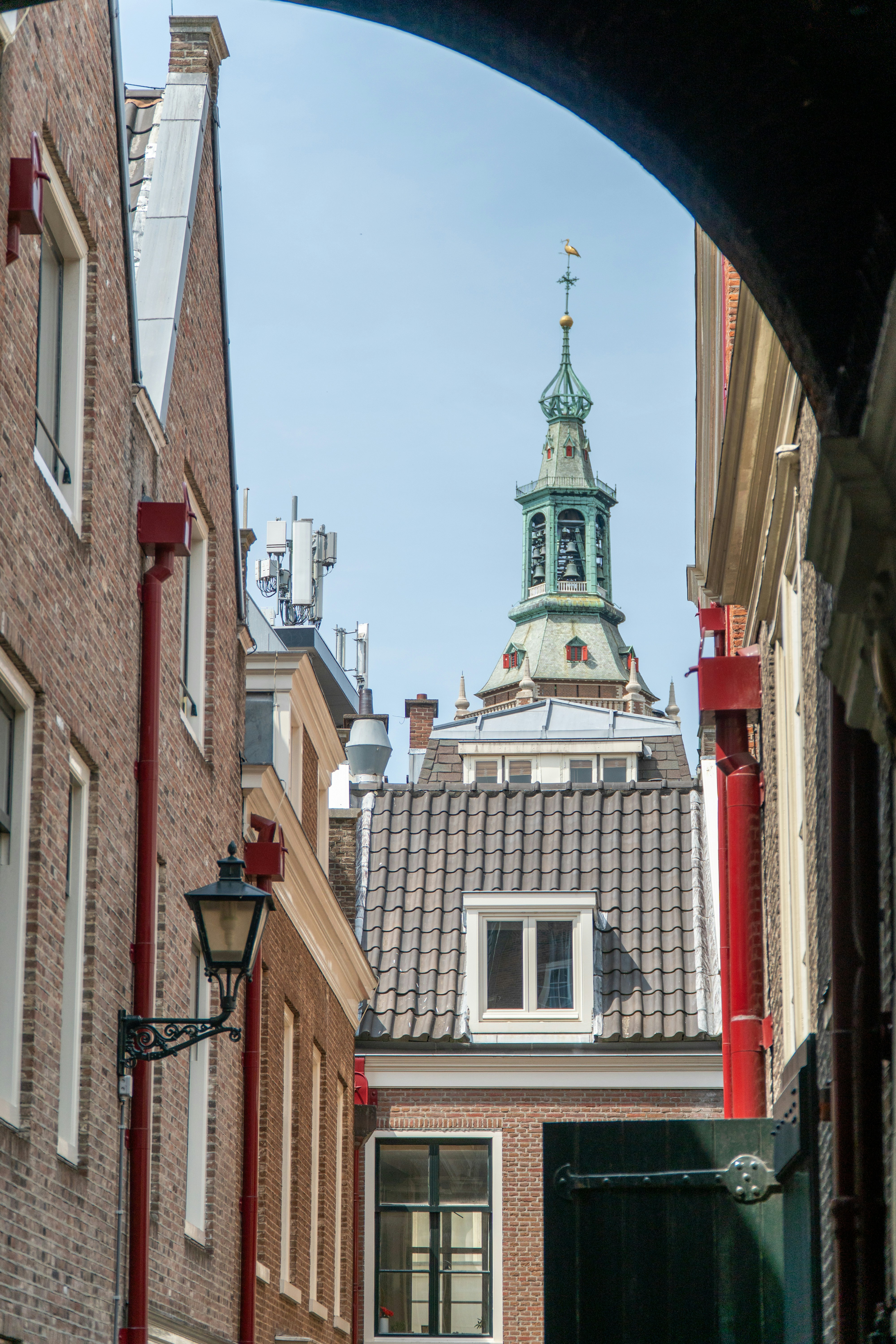 A small alley in The Hague, Netherlands | A church tower is visible through a narrow street.
