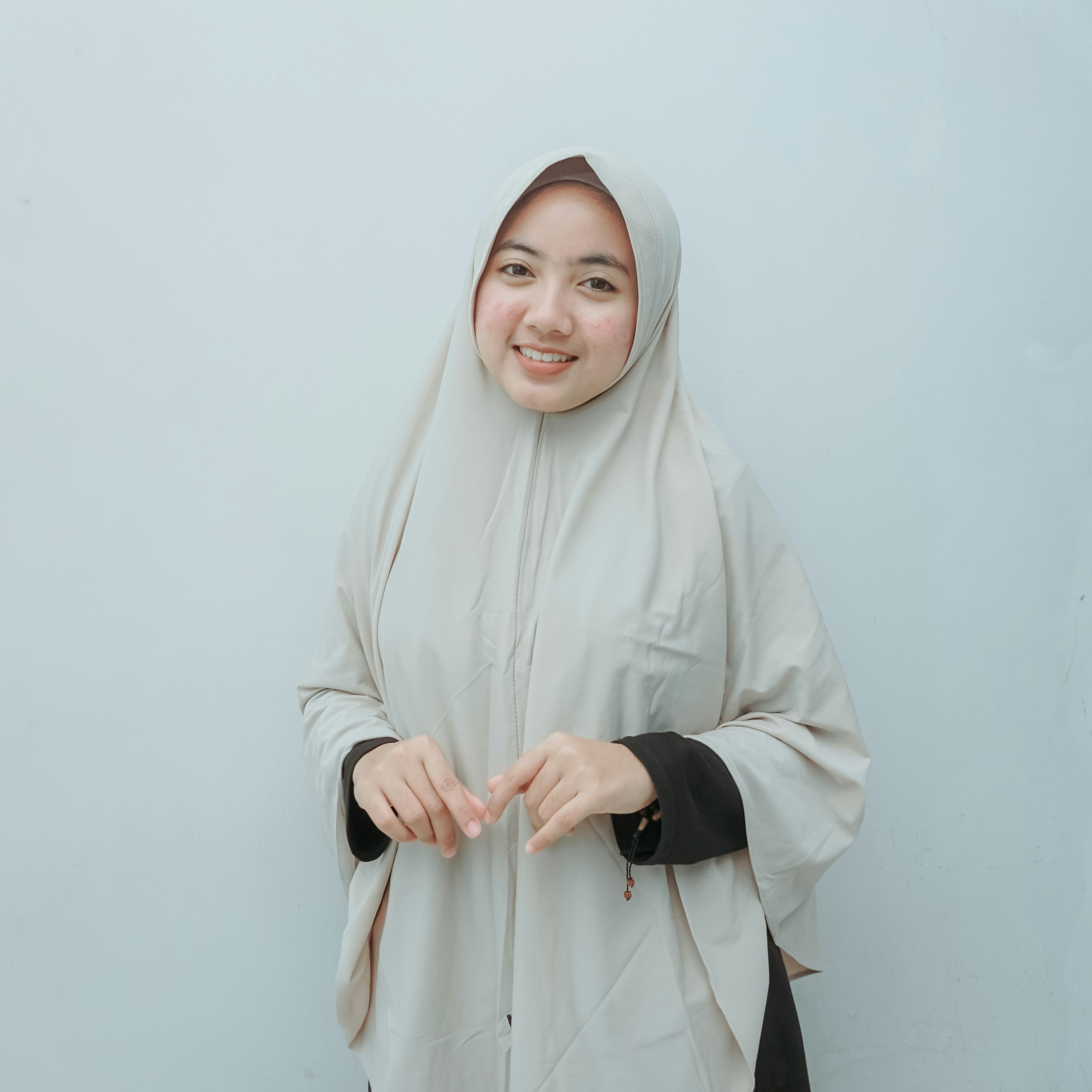 A smiling woman wearing a hijab.