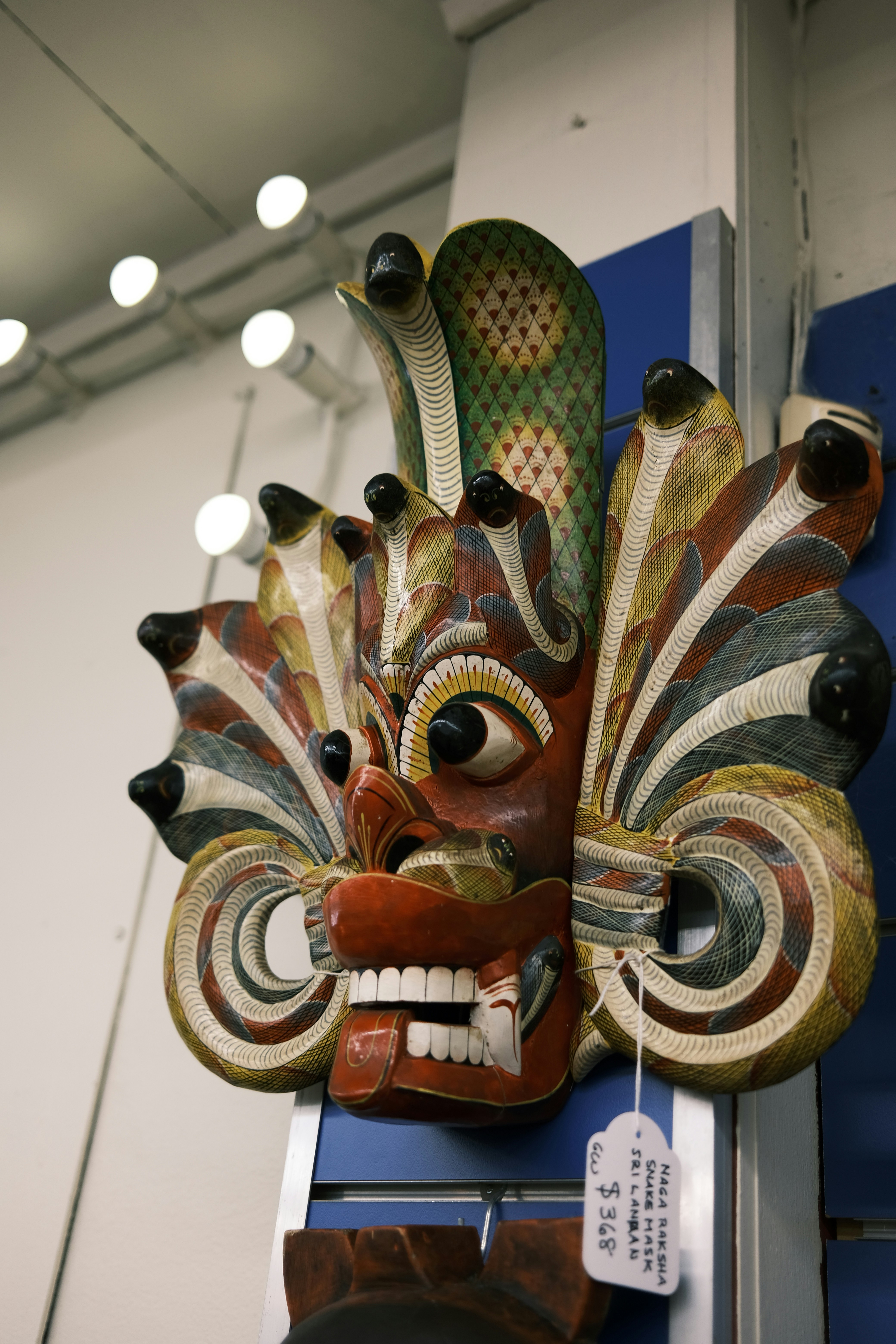 A carved, colorful mask is displayed in a store.
