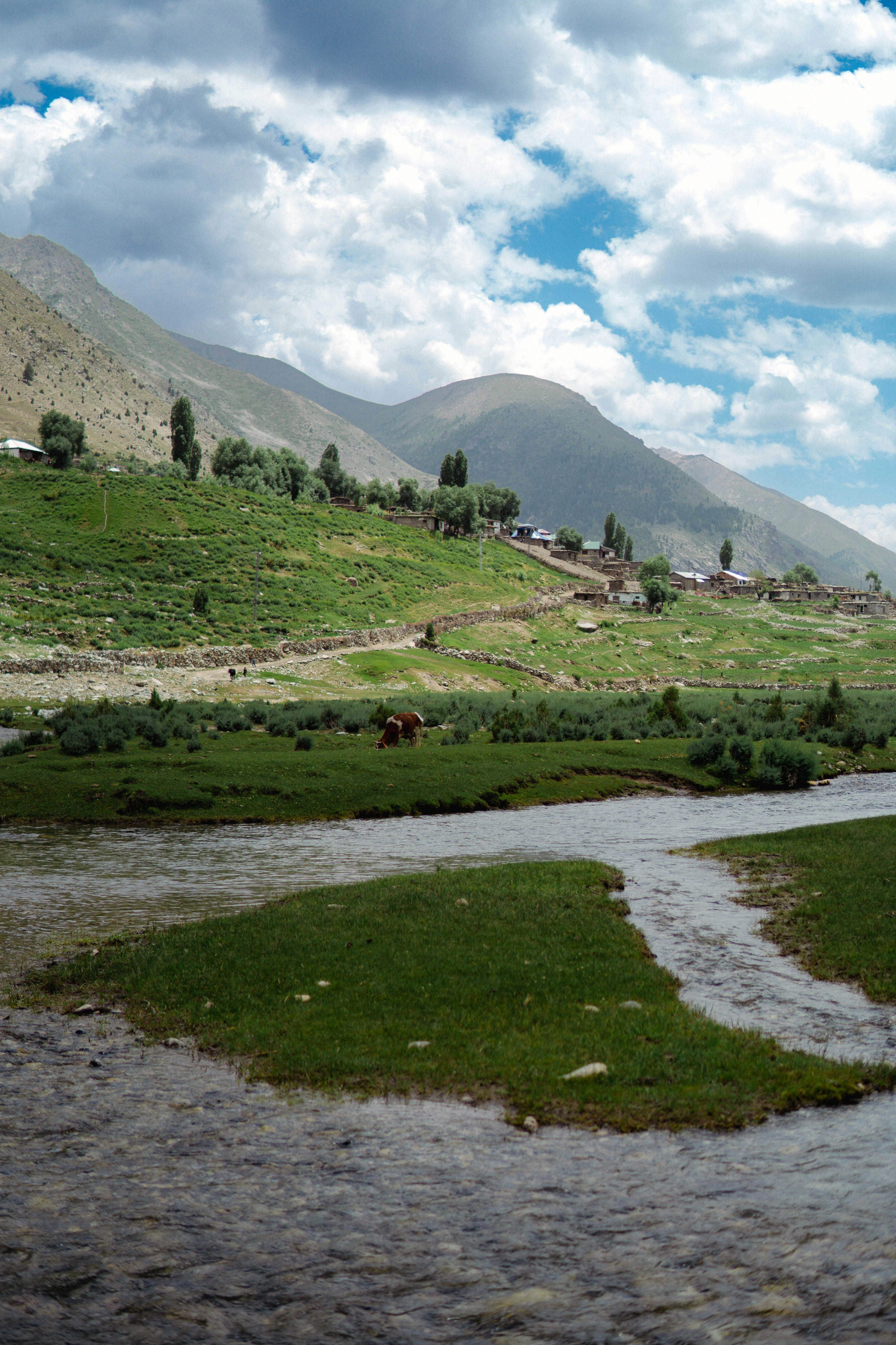 Mountains, green hills, and a flowing river.