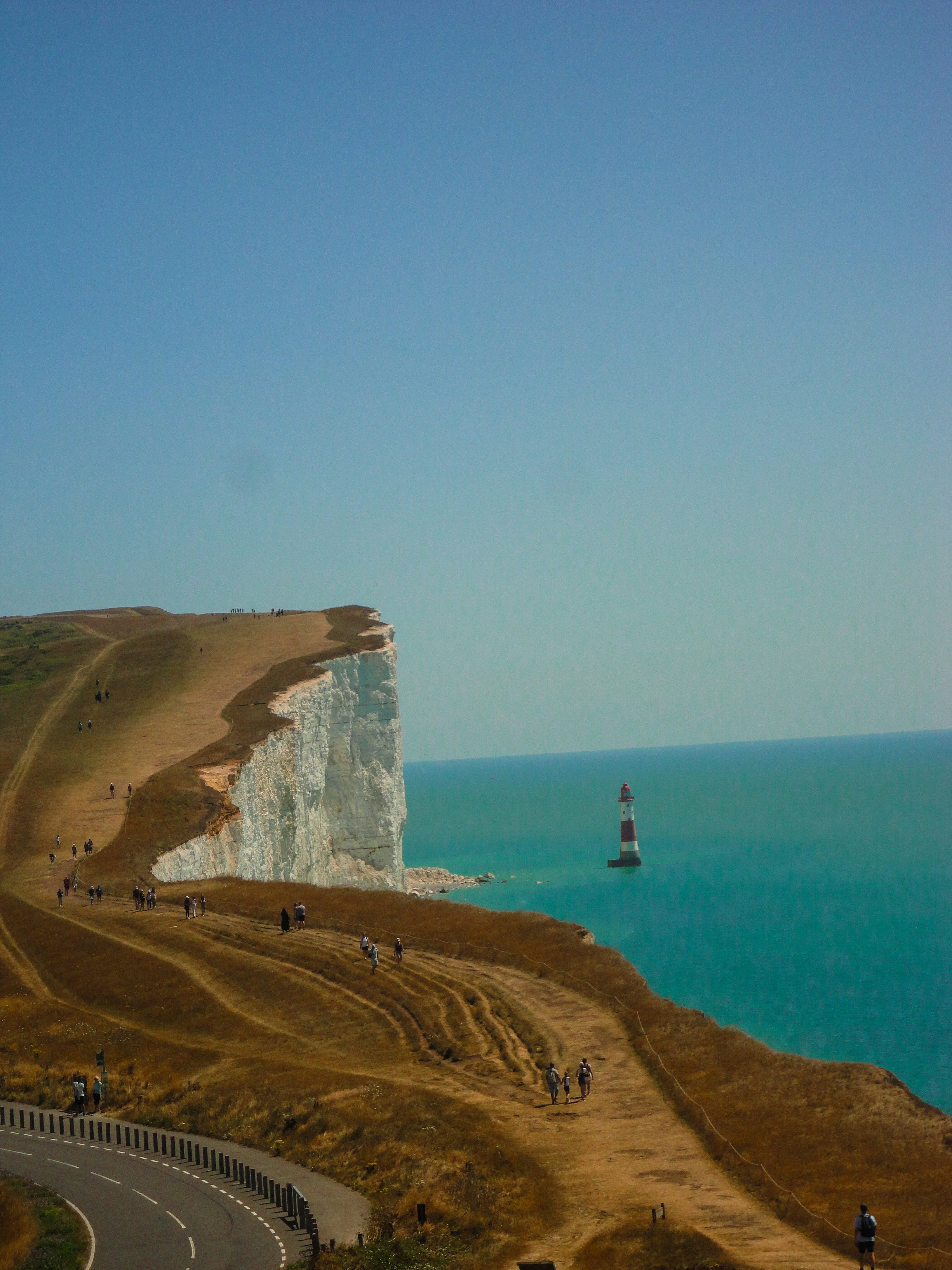 White cliffs and lighthouse overlook the vast ocean.