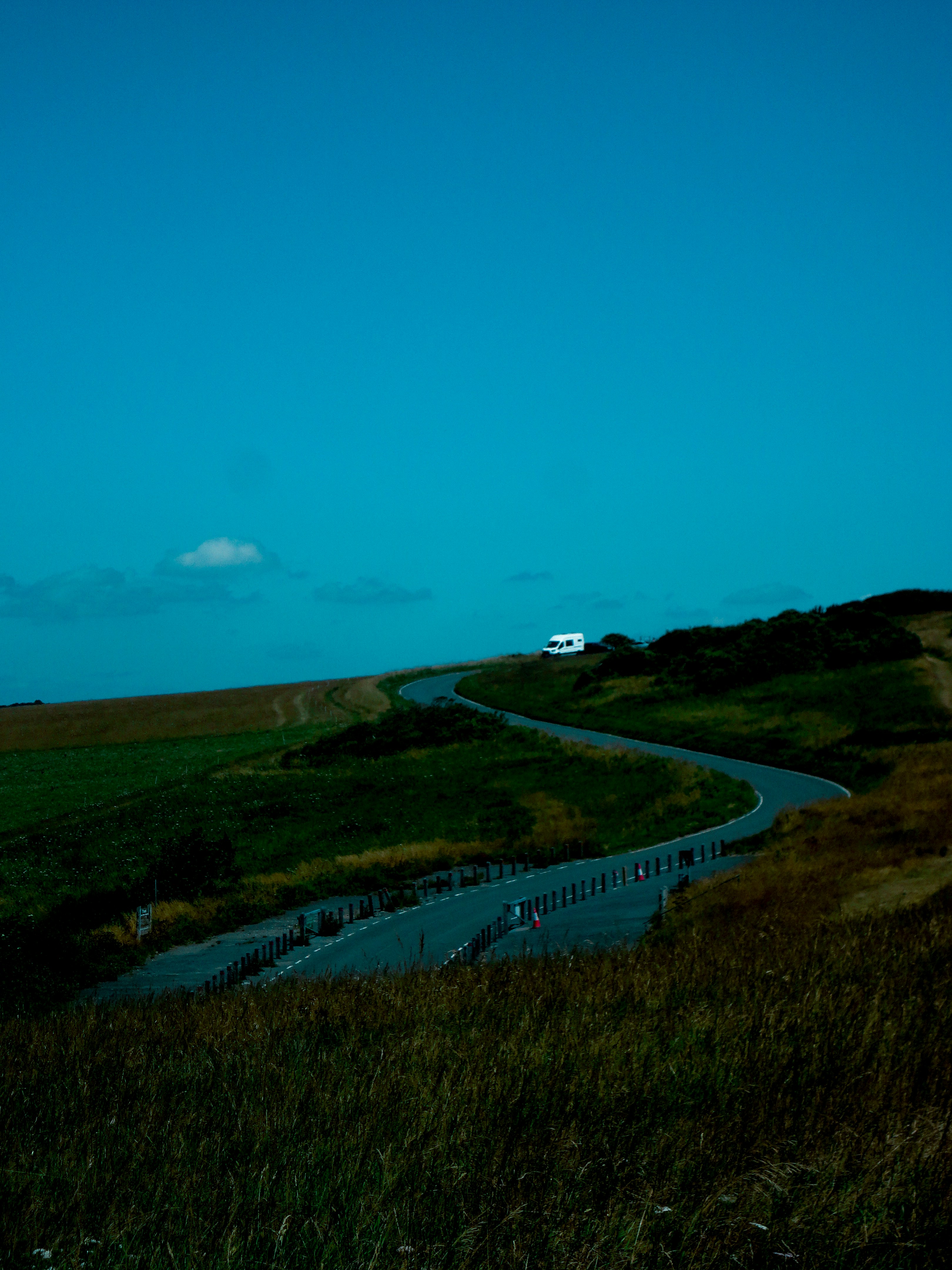 A winding road leads to a distant camper.