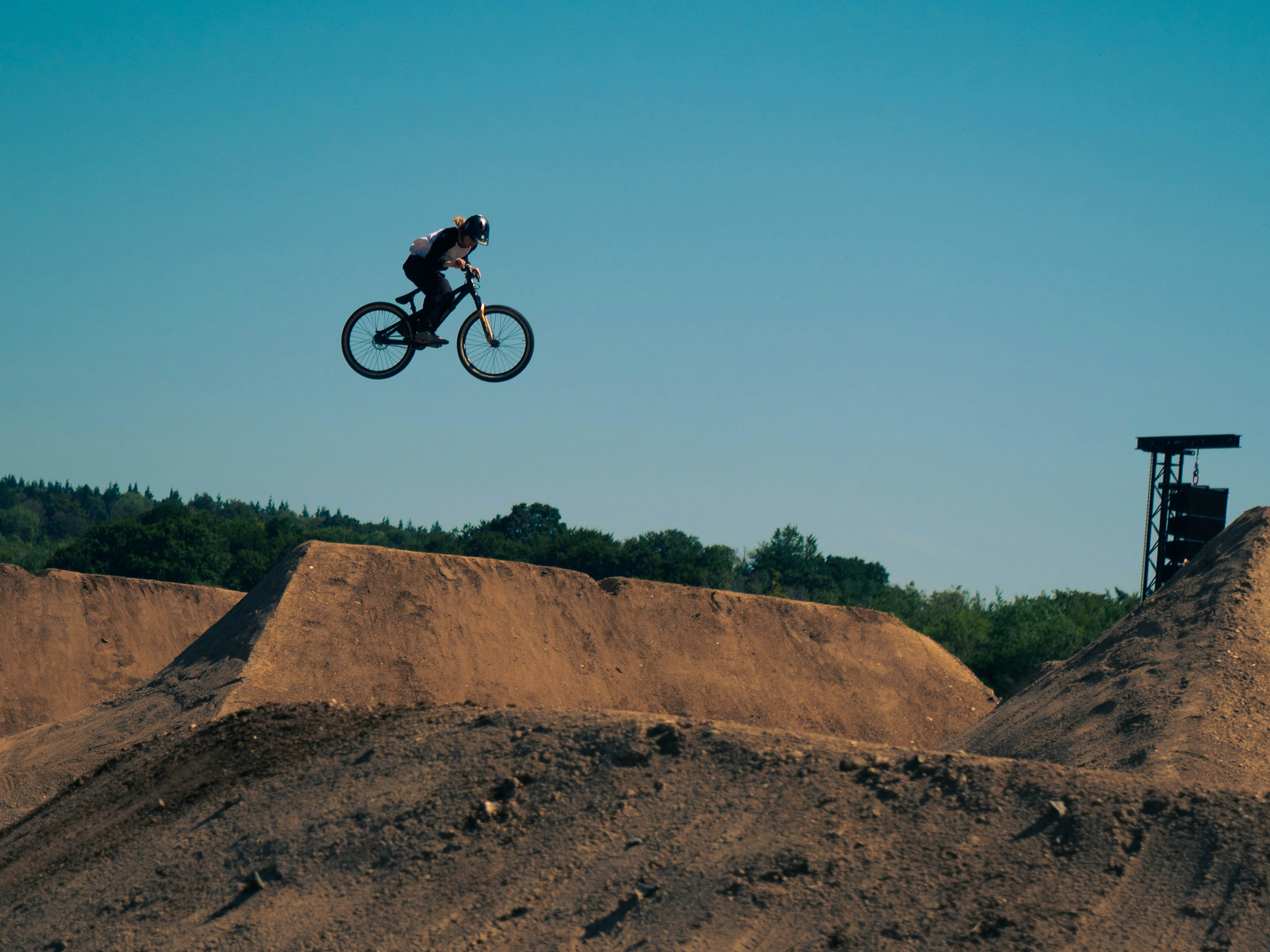 A BMX biker does a jump. | A cyclist does a jump on their bike.
