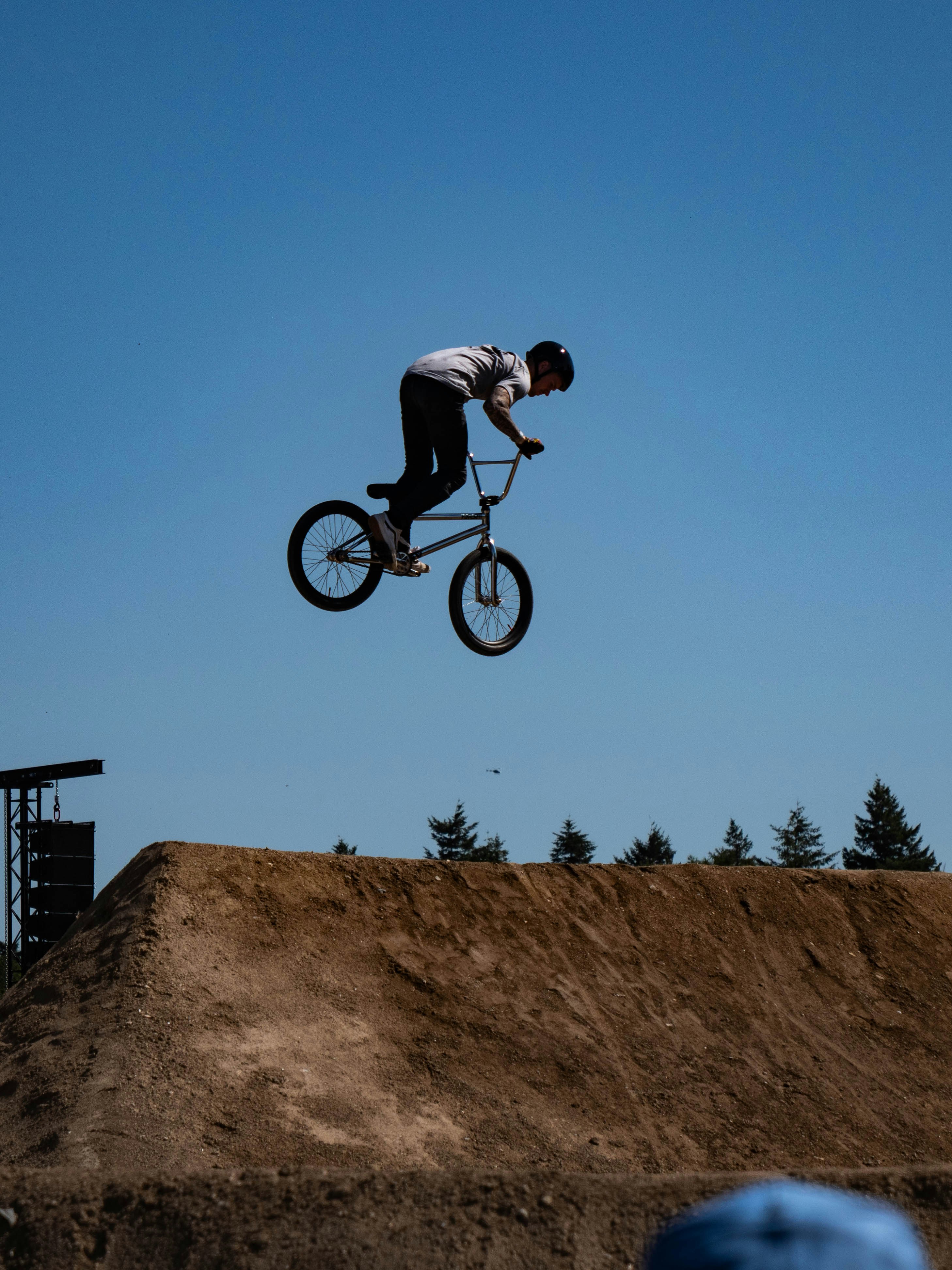 A BMX biker does a jump. | A bmx rider performs a trick mid-air.