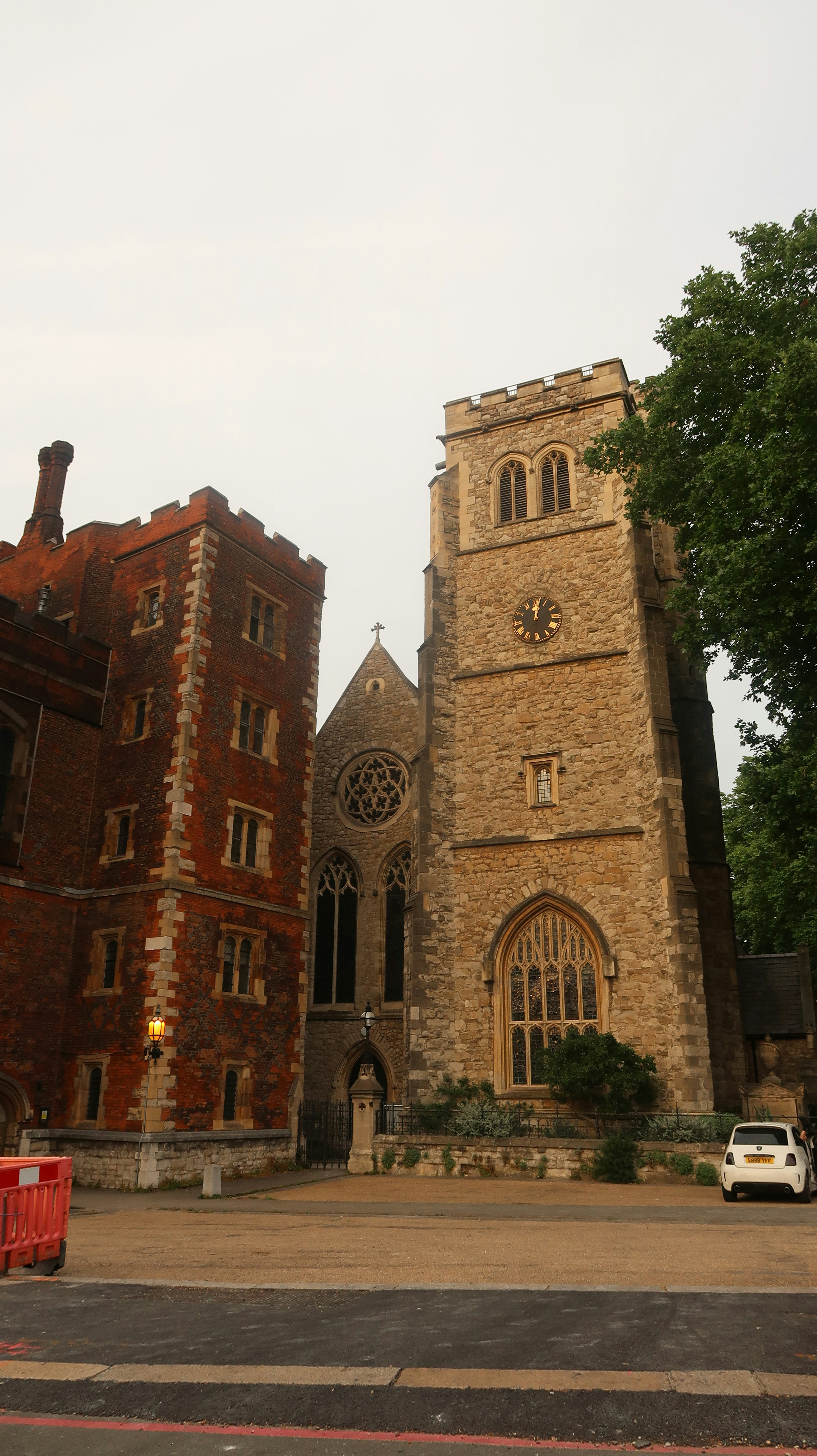 Historic stone church and red brick building stand side by side, showcasing intricate architectural details and a clock tower.