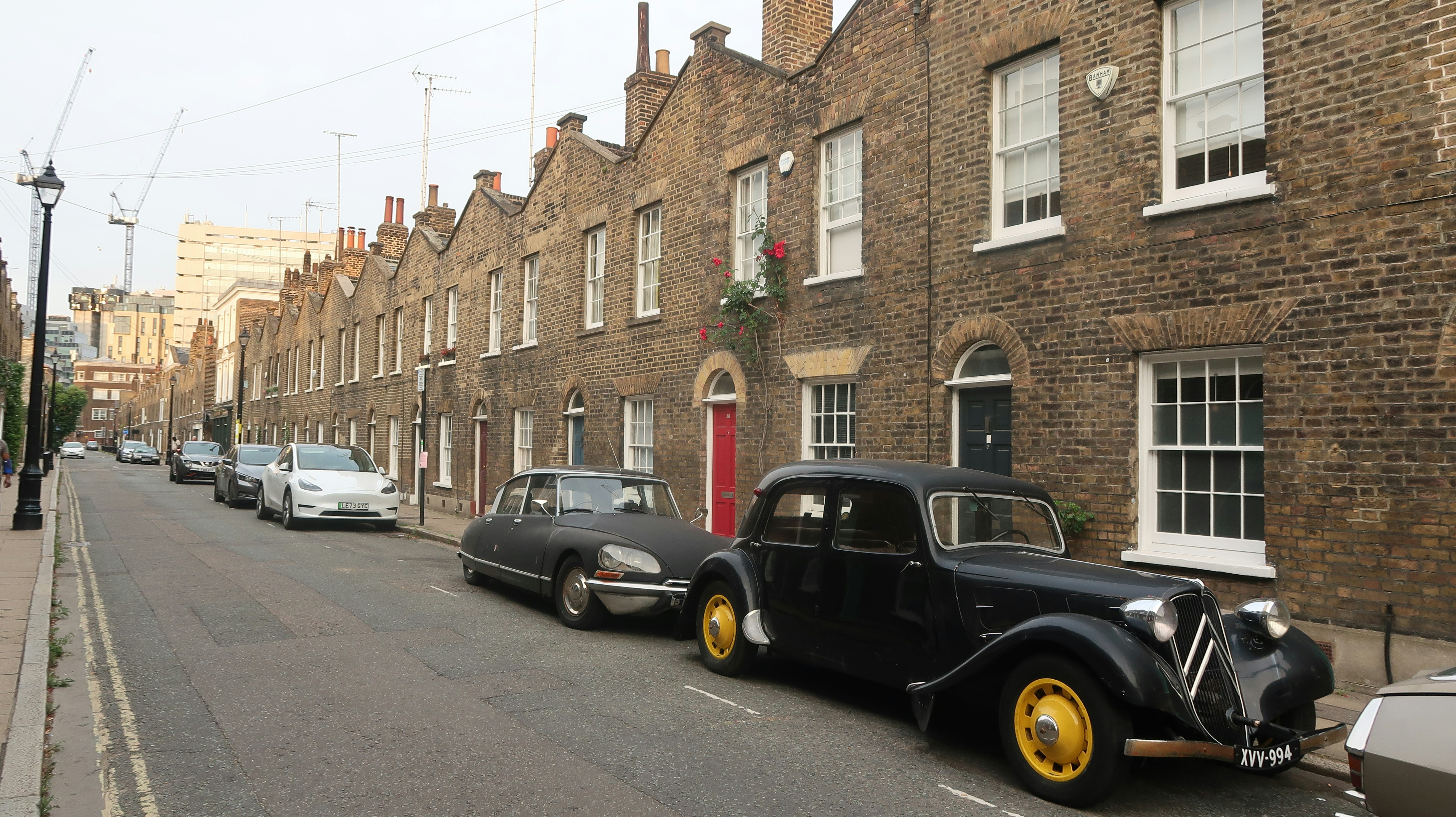 Row of vintage cars and brick terrace along a quiet street