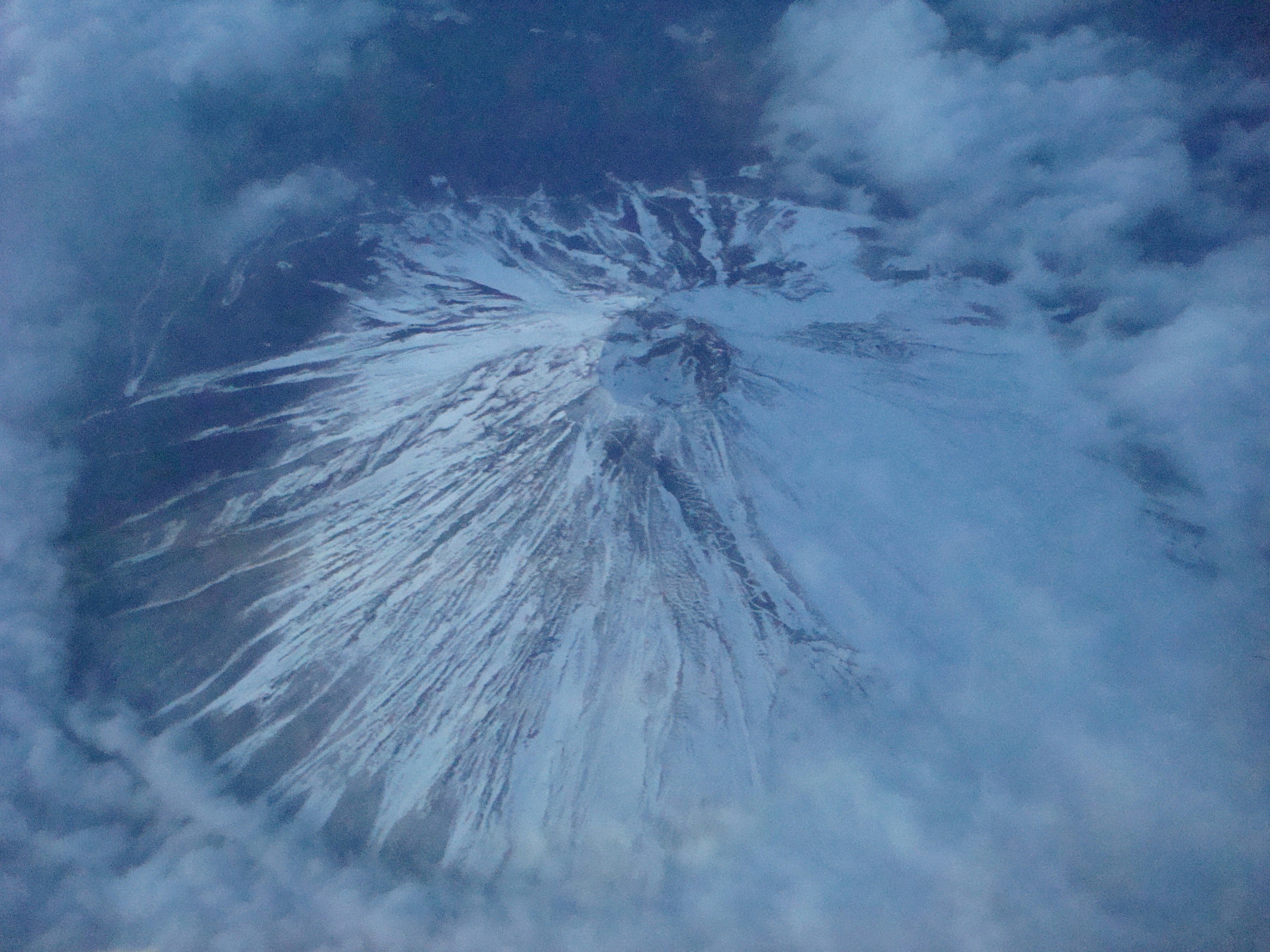 Here's a caption: snowy mountain peak surrounded by clouds.