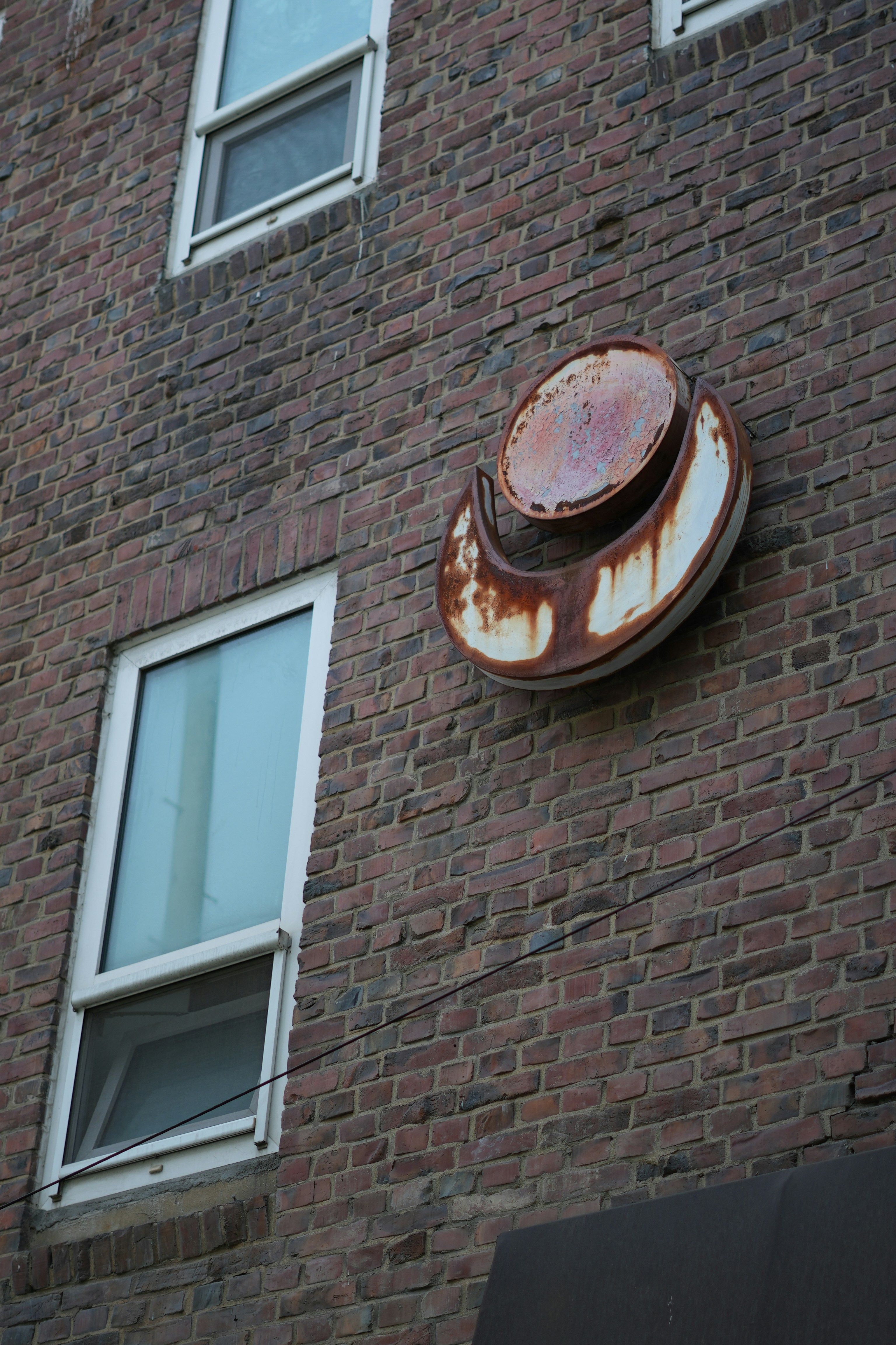 Rusty metal sign on a brick wall.