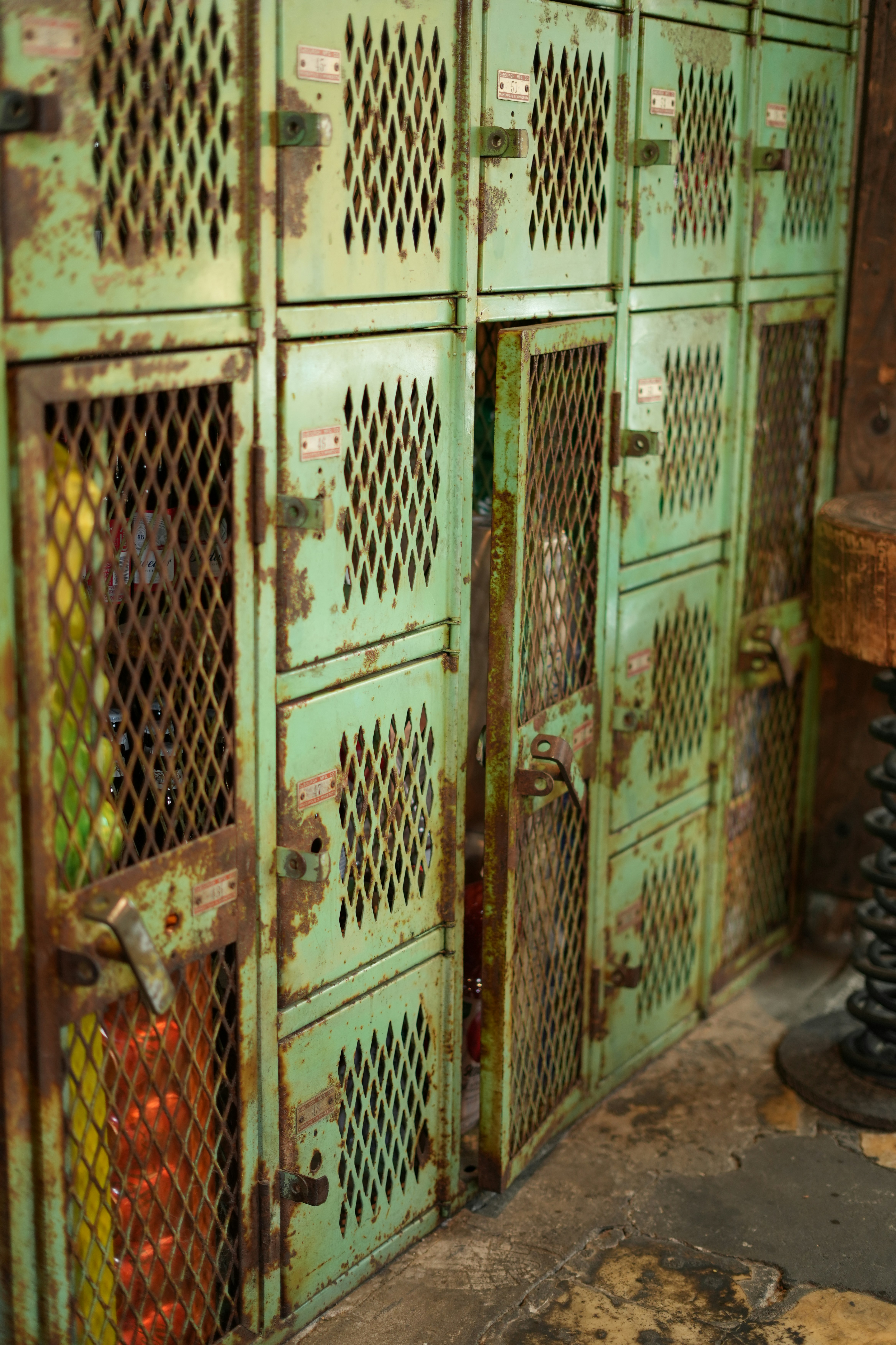 Rust and Mesh: Rows of Weathered Green Lockers in a Dismal Workshop Corridor
