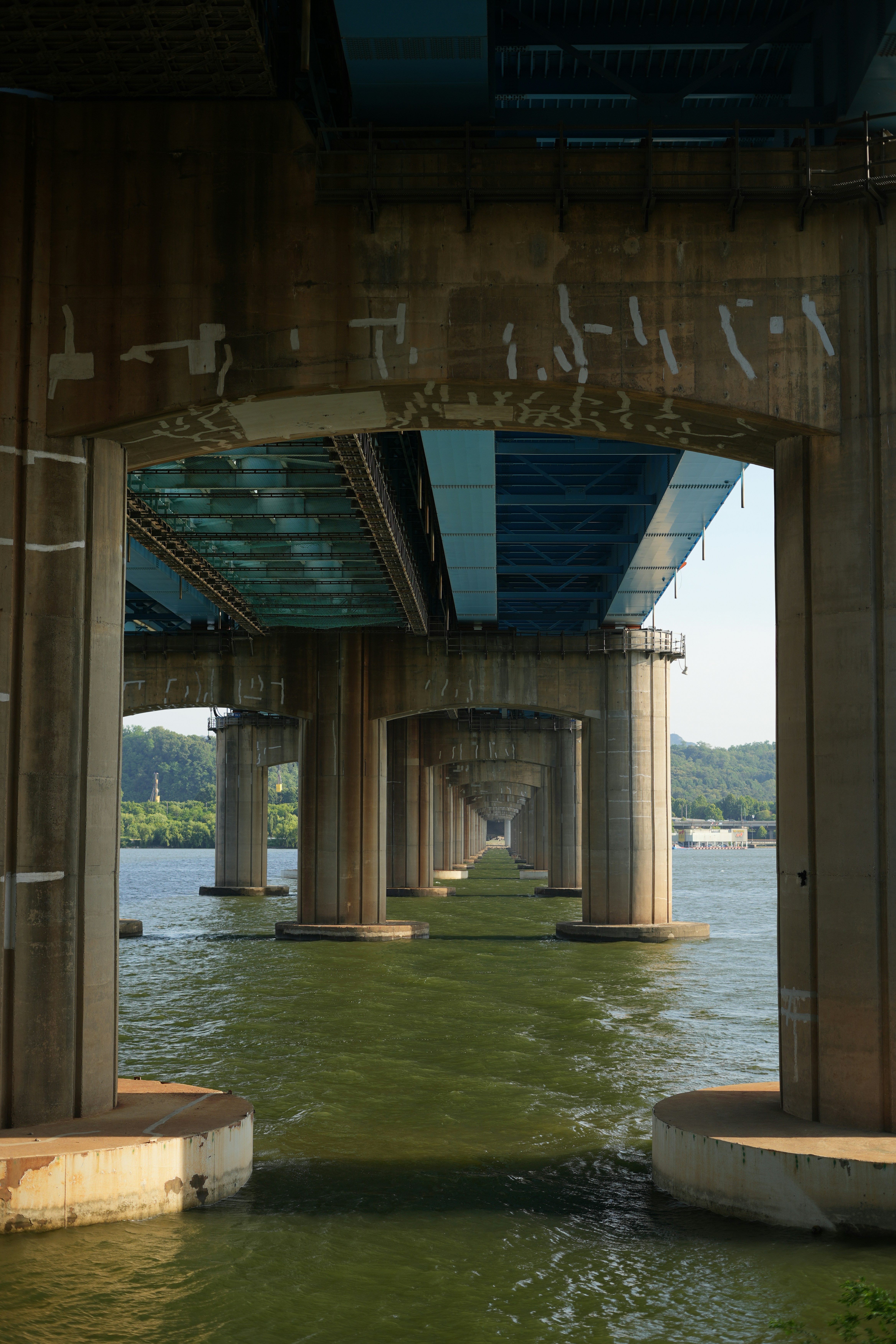Underneath a bridge, looking at the river.