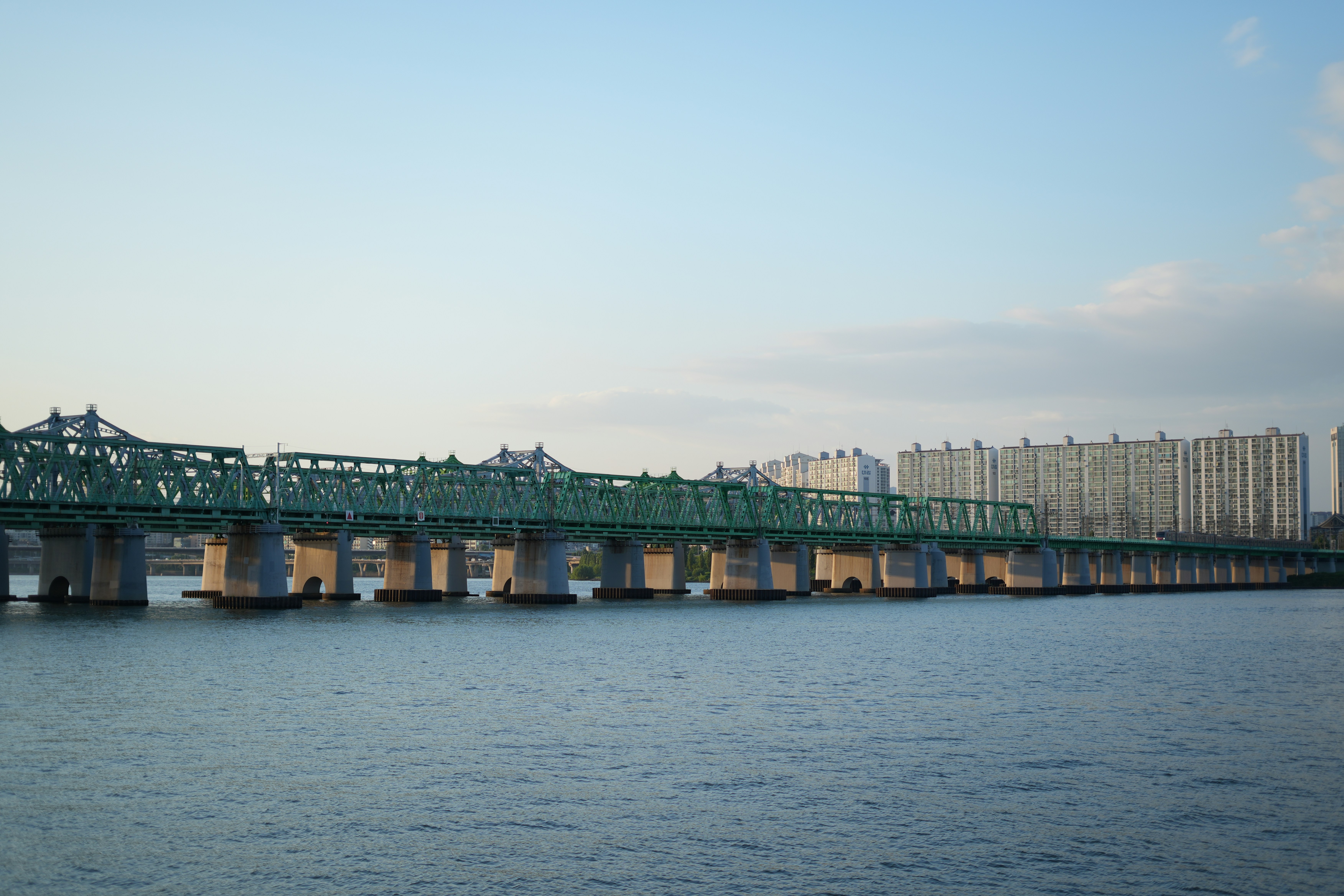 A green bridge spans over calm waters.