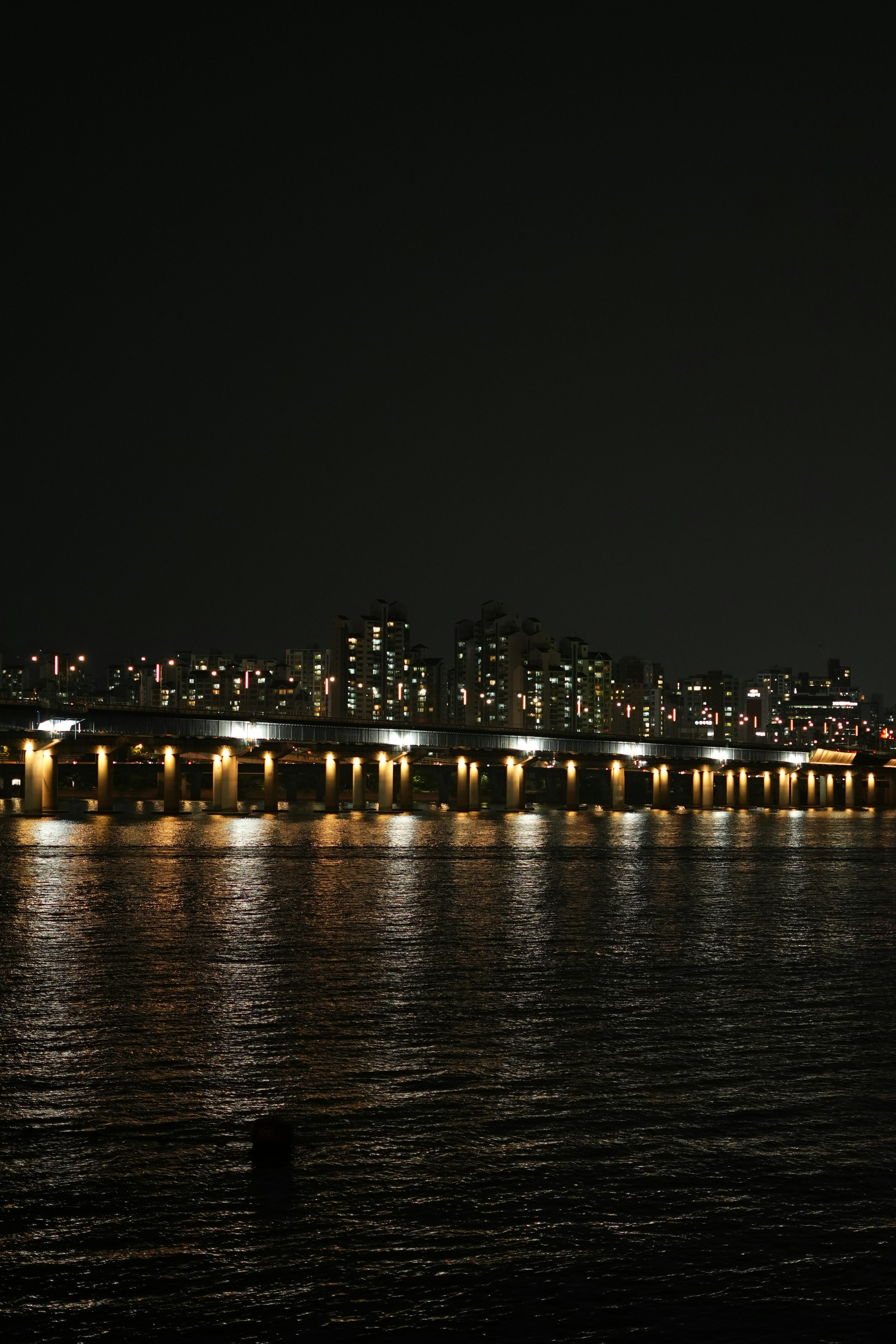 City lights reflect on the water at night.