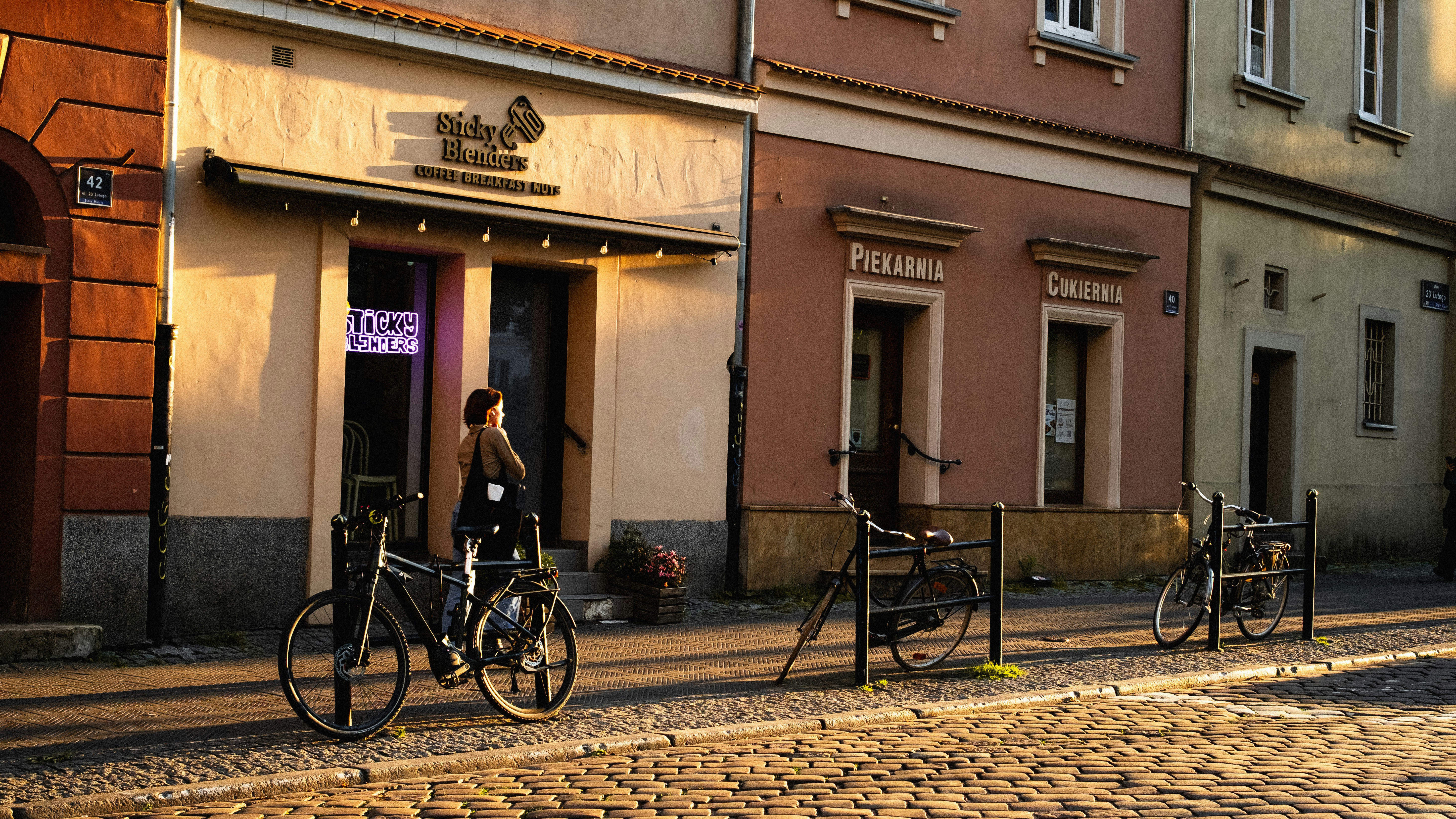 A woman walks past bikes in a street.