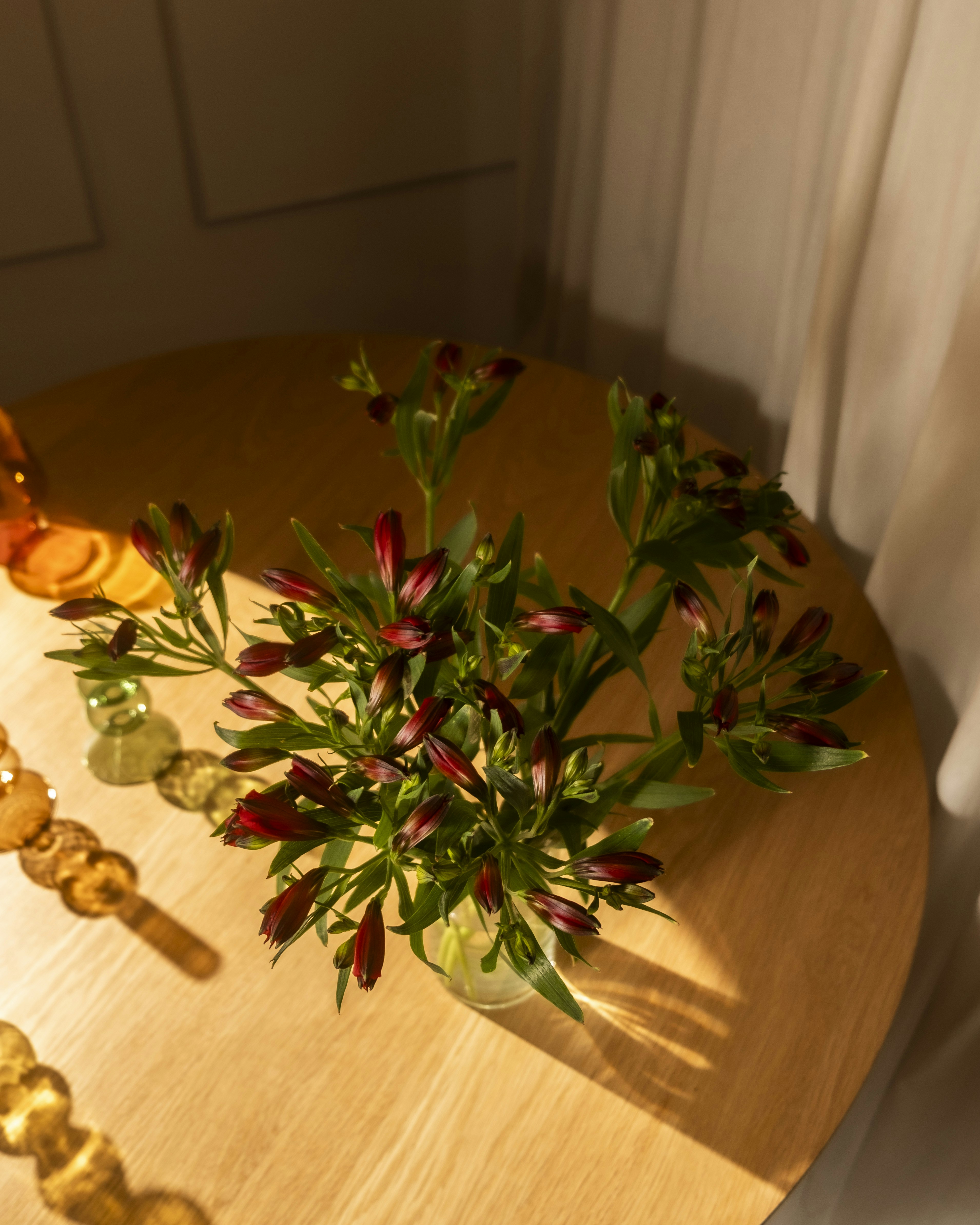 Flowers are on a table with decorative glass.