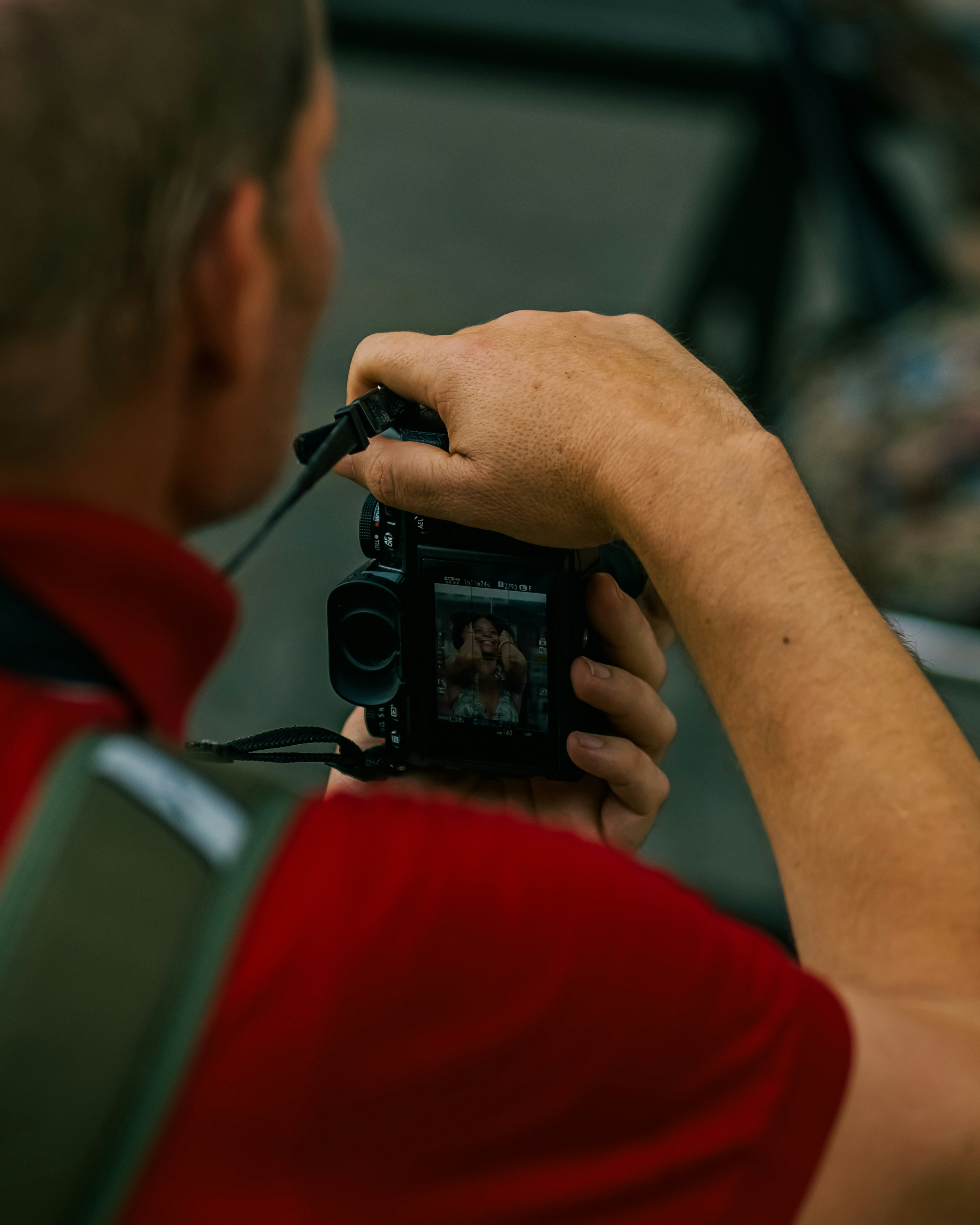 A photographer reviews a candid street shot on his camera’s screen. Shot from behind, this image captures a moment of focus. | A man takes a photo with his camera.