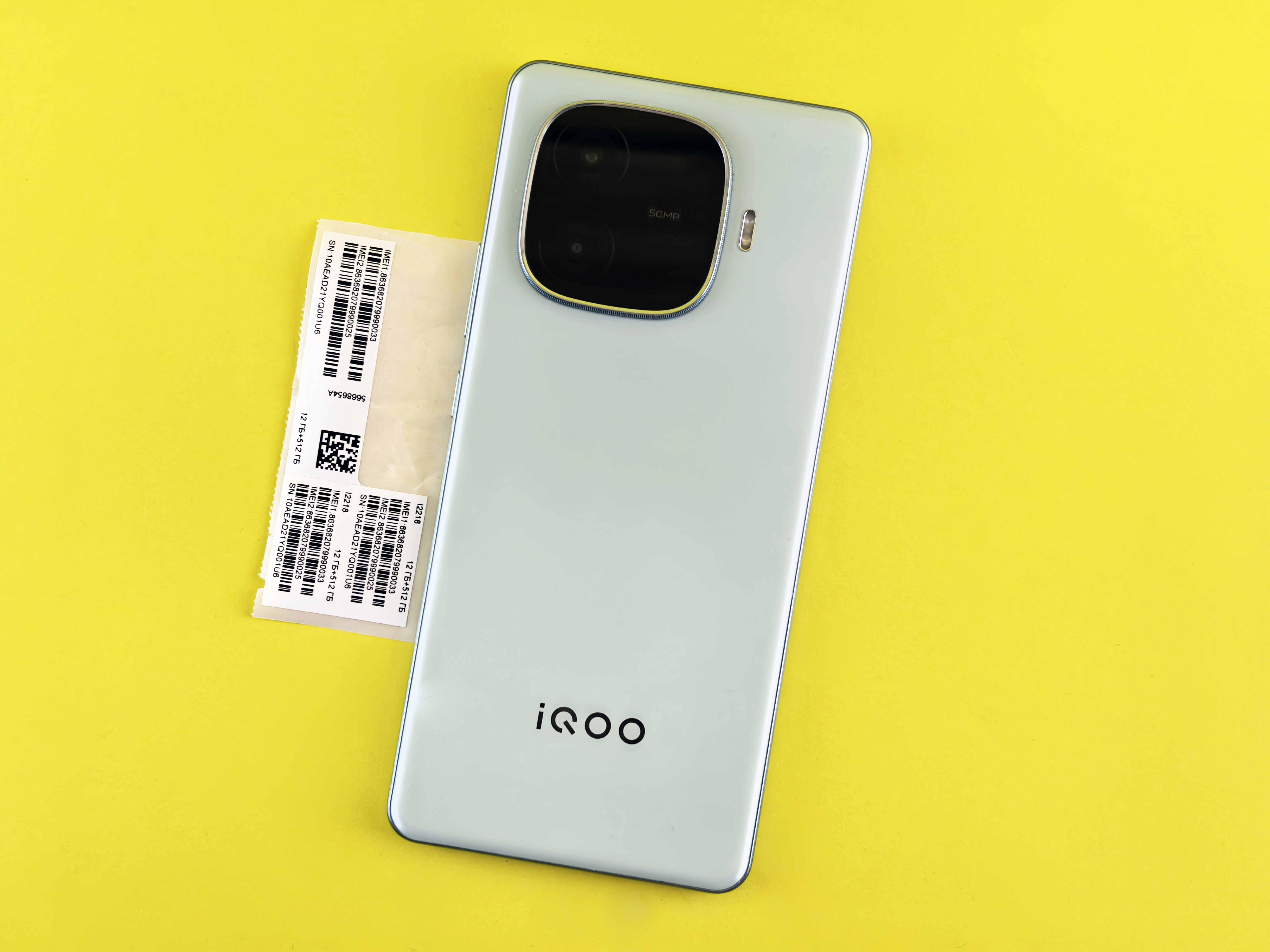 A light green phone with a paper next to it.