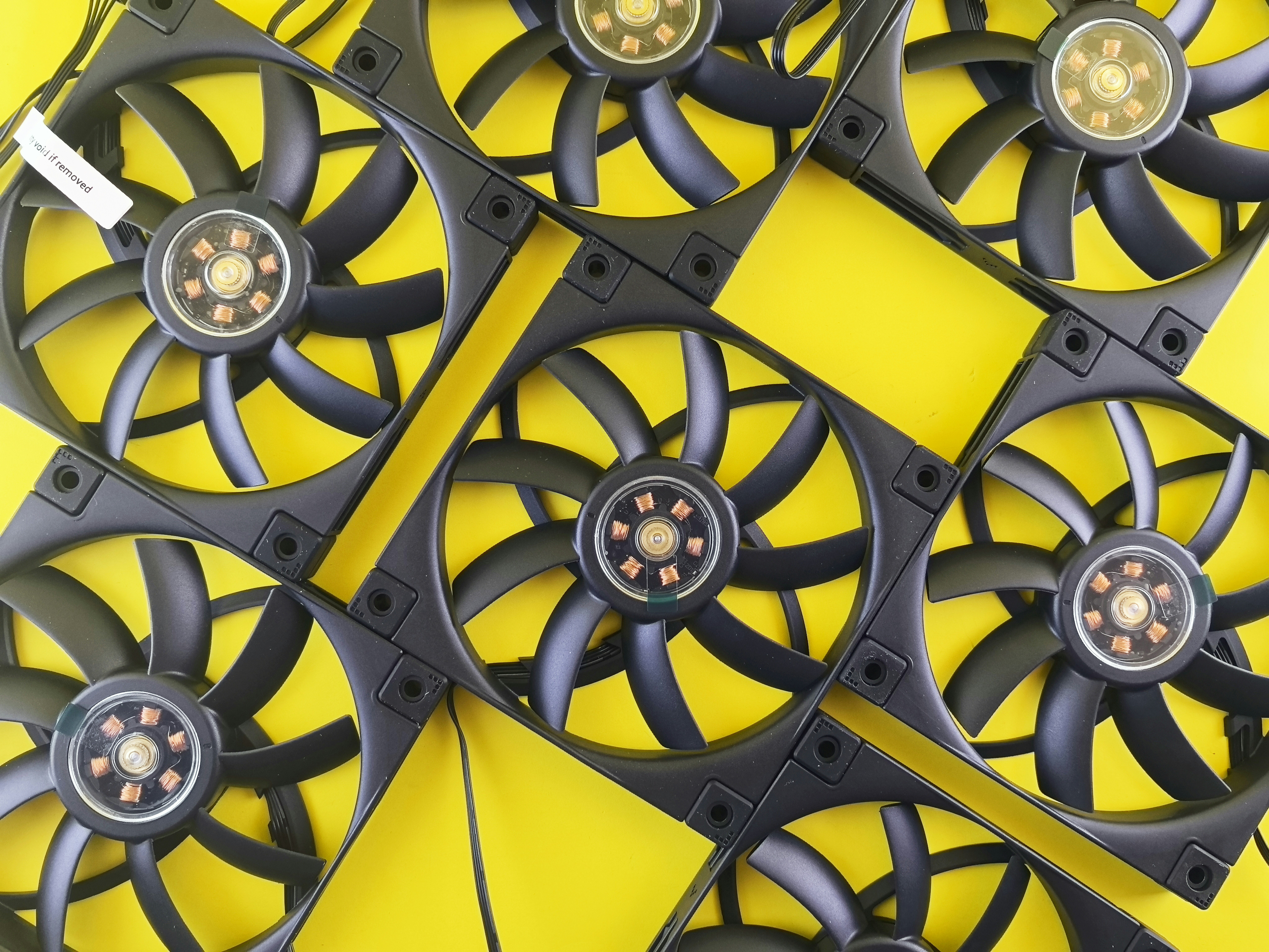 Computer fans are arranged on a yellow surface.