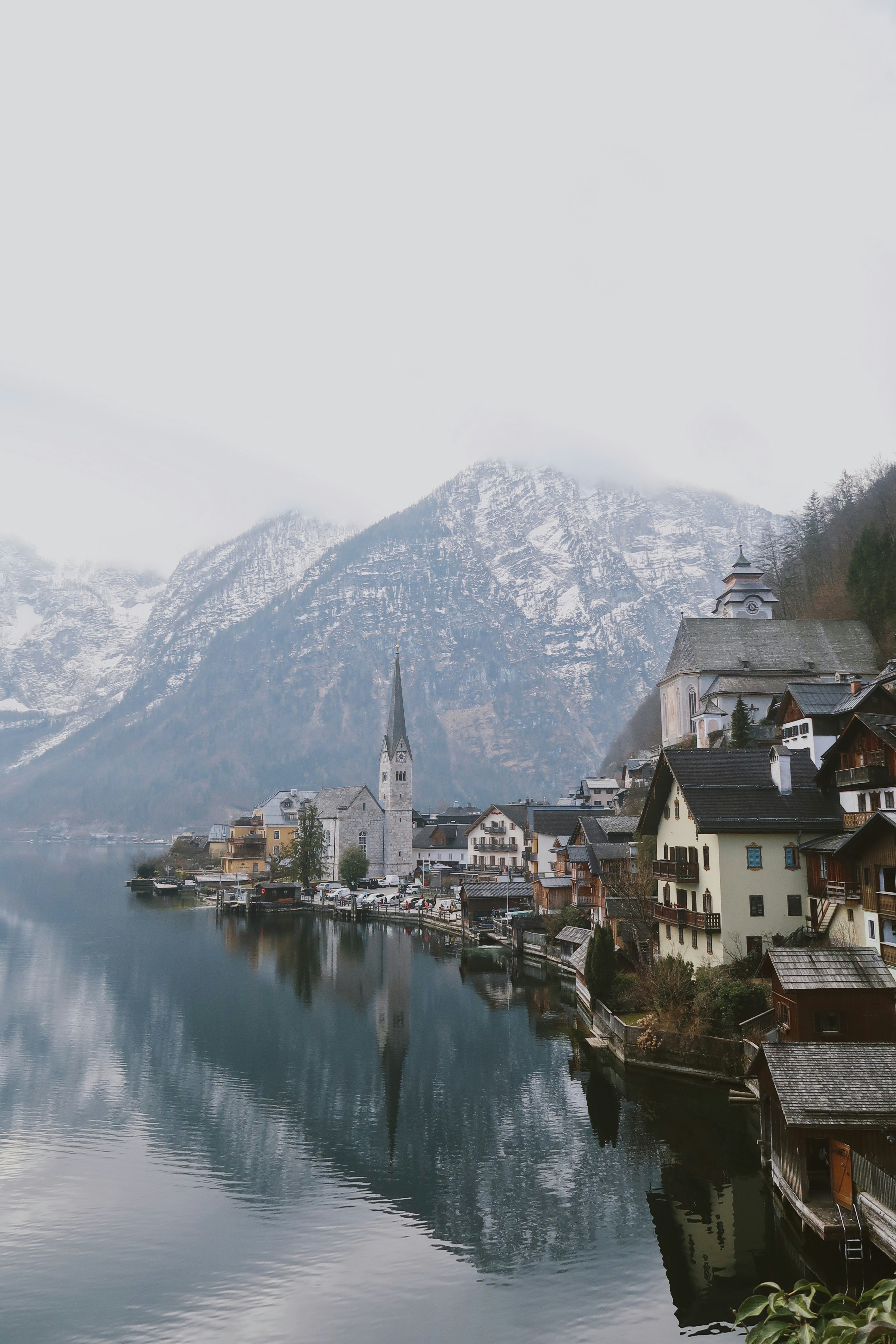 Scenic village nestled on a lake with snowy mountains.