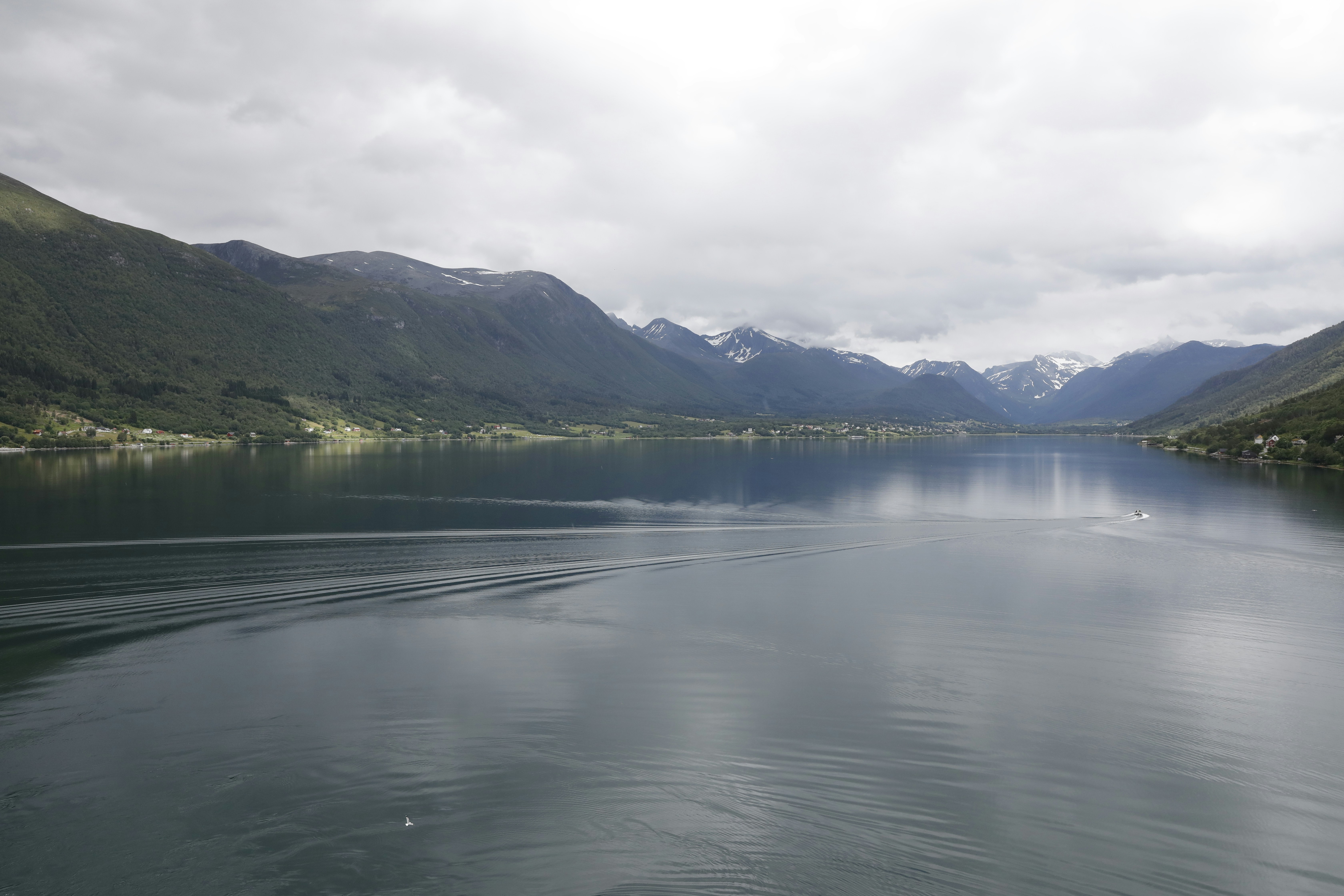 Romsdalfjord, Norway | A calm lake reflects mountains under overcast skies.