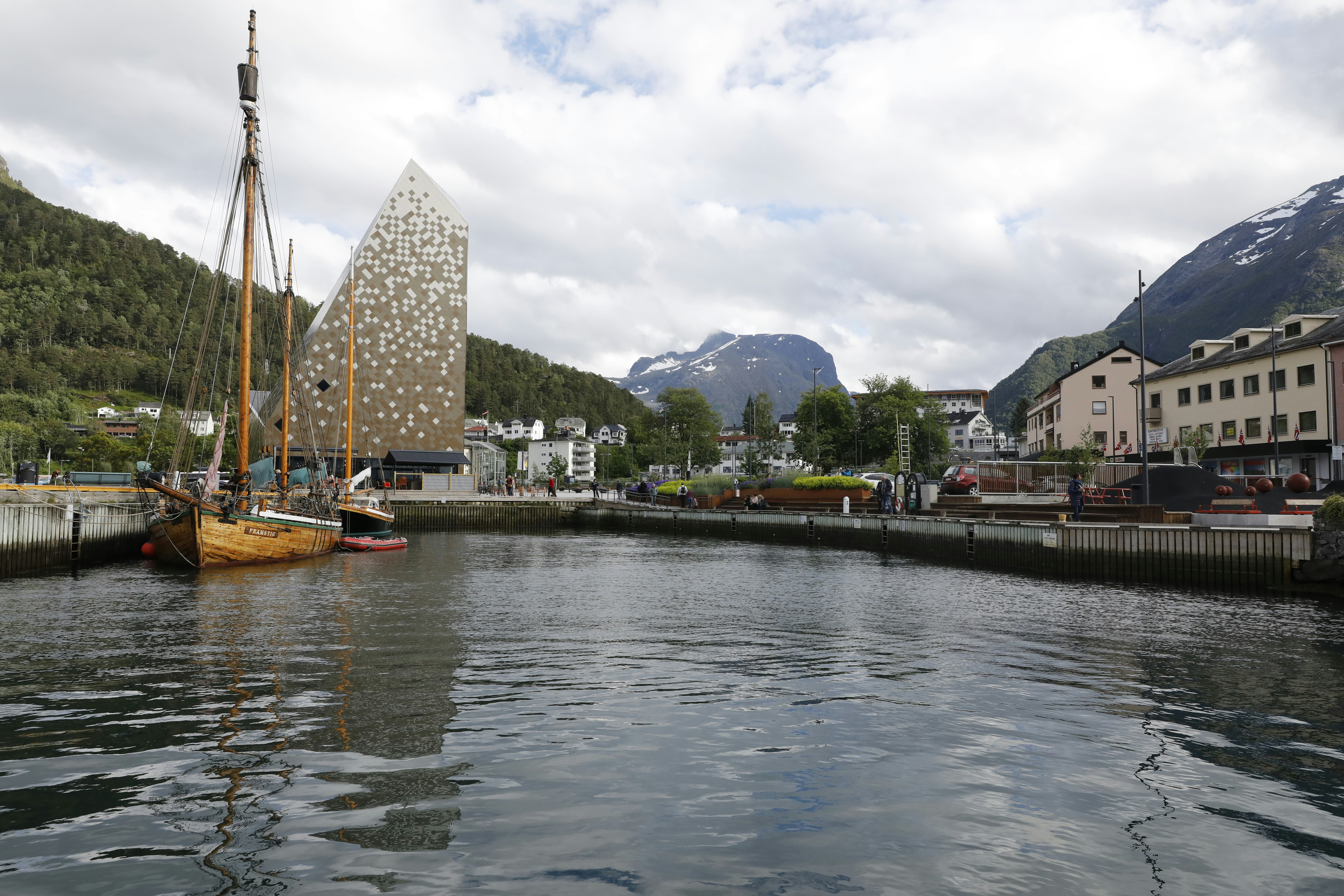 Perforated Monolith by the Water: A Sailboat Against Alpine Backdrop