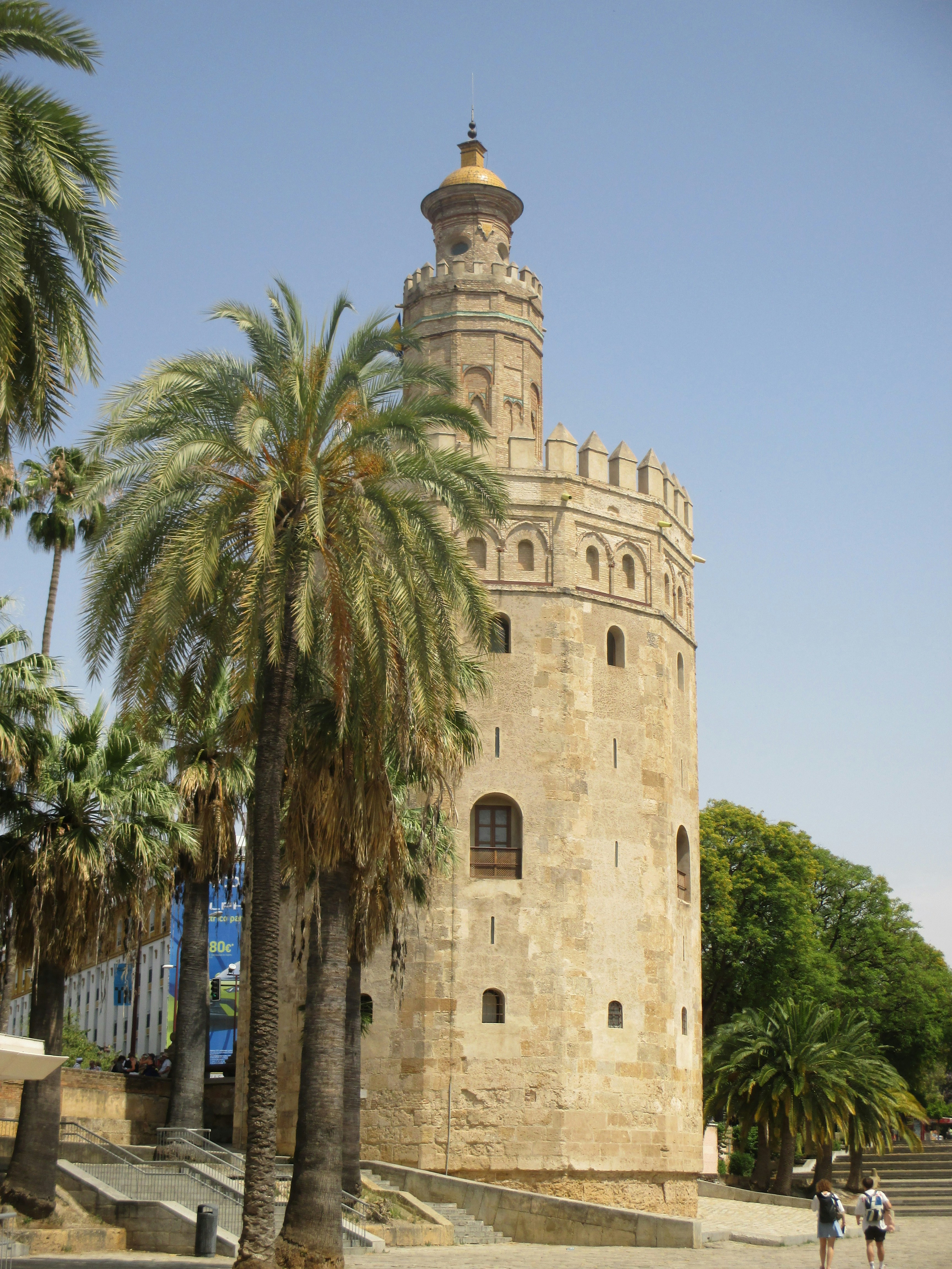 Torre del Oro | A stone tower and palm trees on a sunny day.